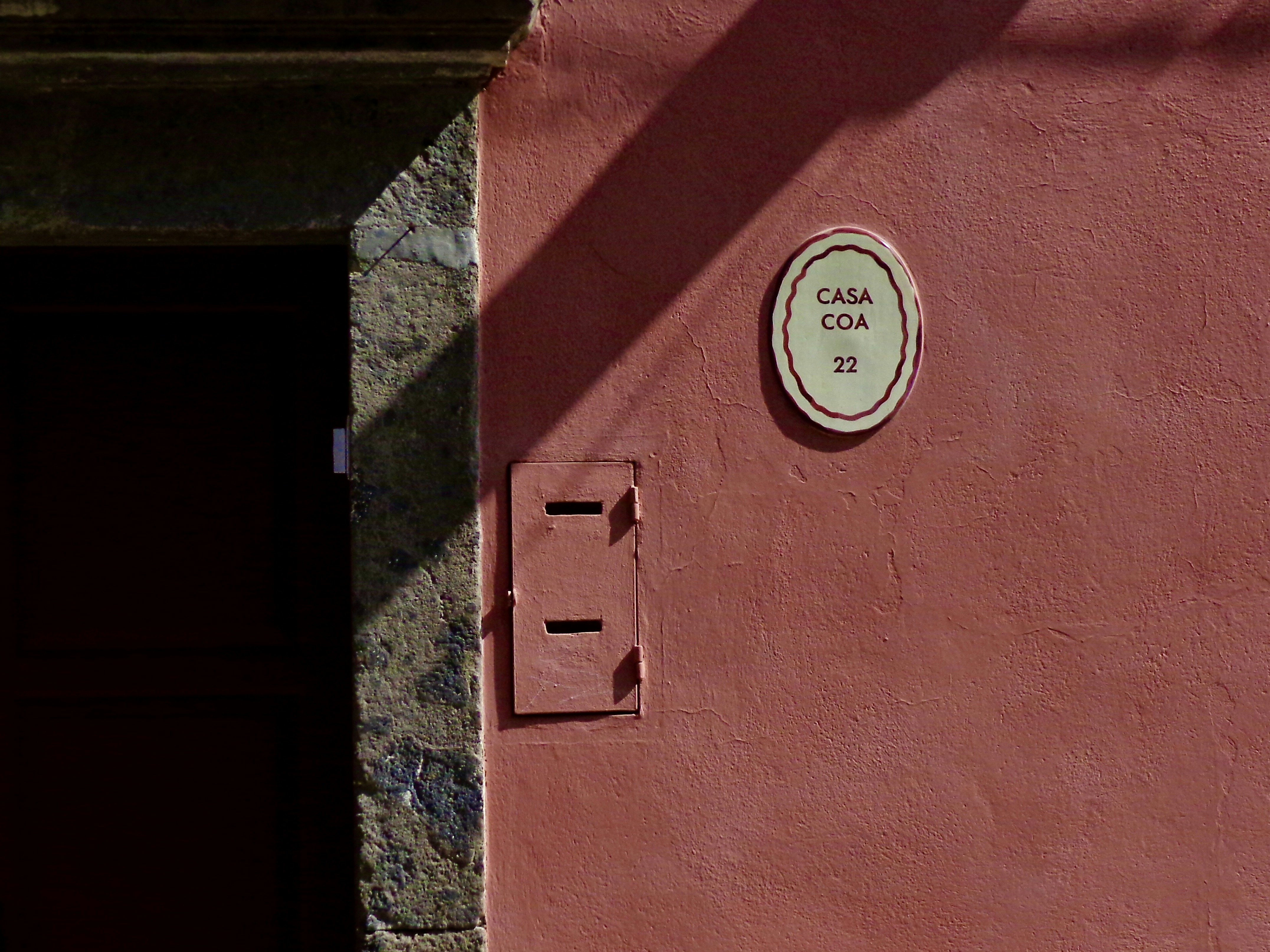 Red Facade, Quiet Doorway: A Sunlit Corner of Casa COA