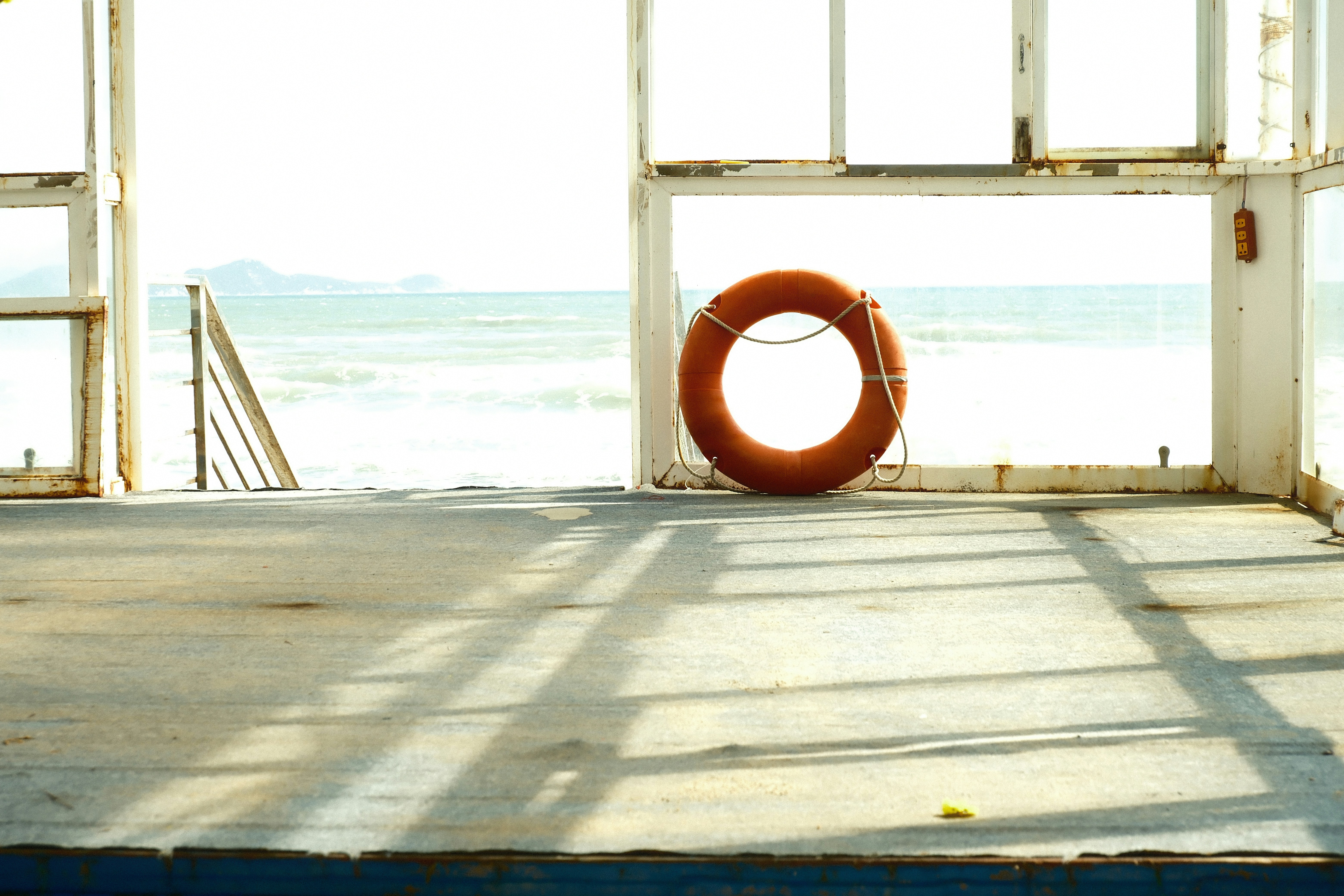 Lifebuoy by the Window: Quiet Beachfront Light Through a Pier-Side Hall