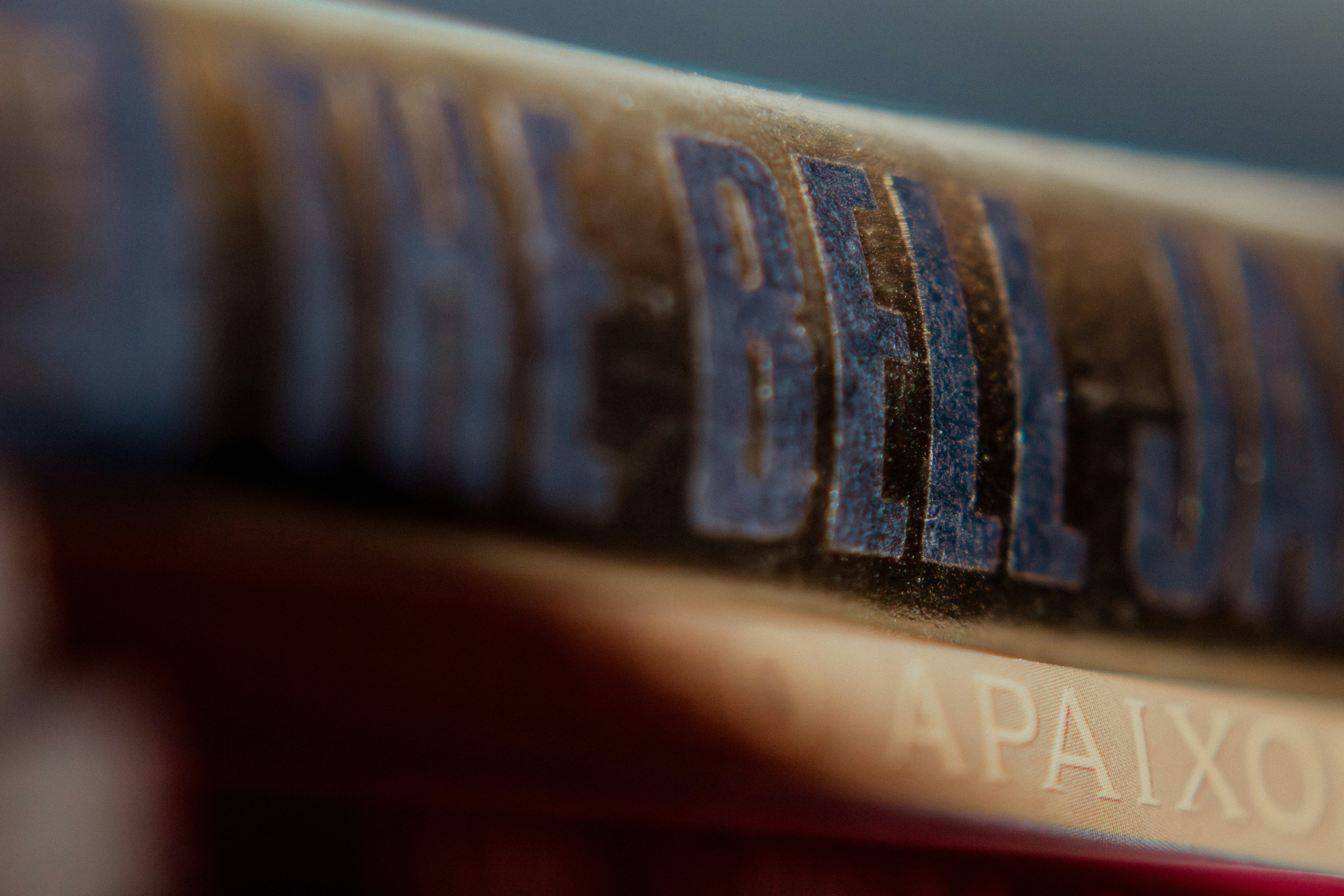 Dusty bookshelf close-up: weathered book spine with faded blue letters