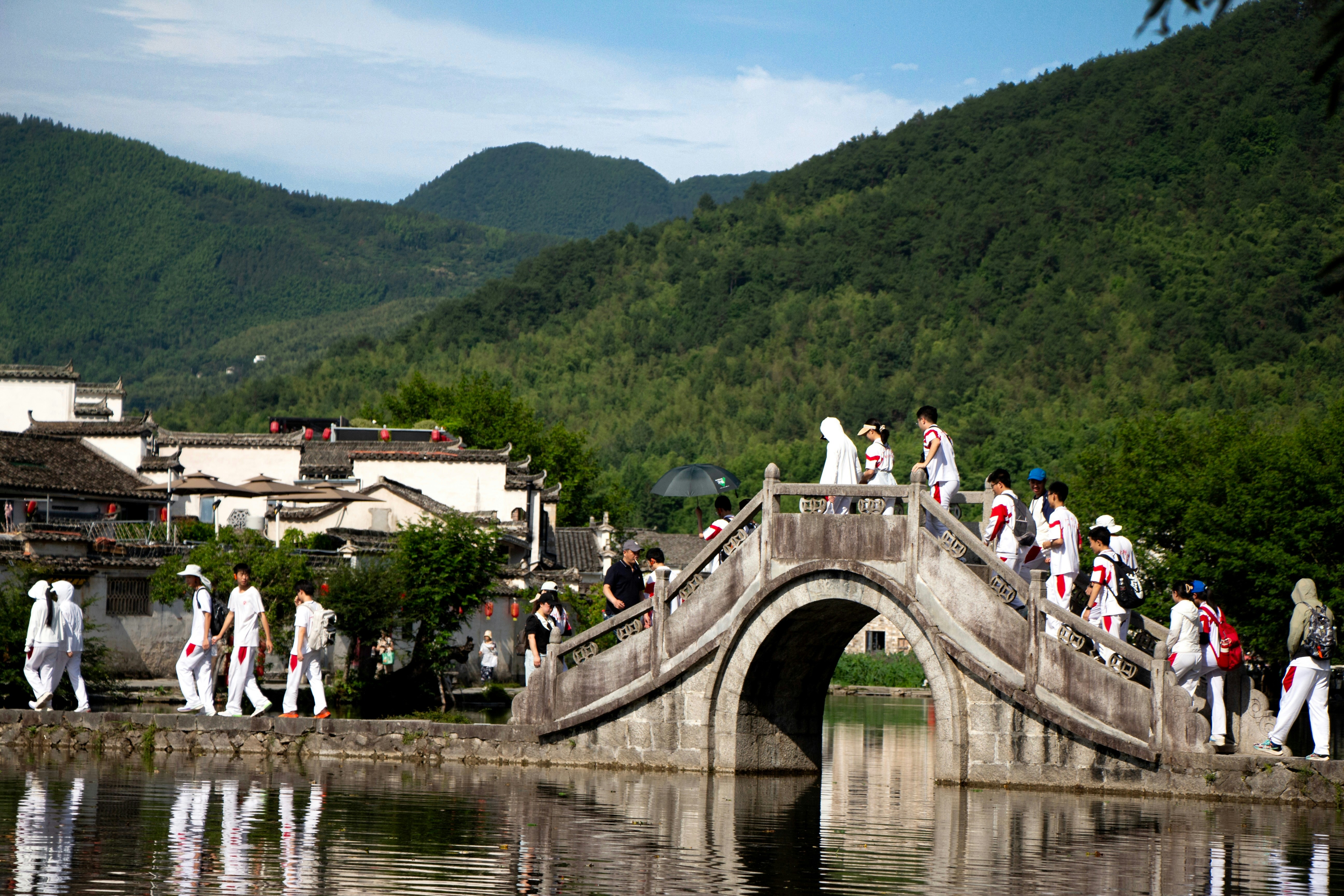 Stone Bridge Convergence: Silent Walkers and Mountain Backdrop