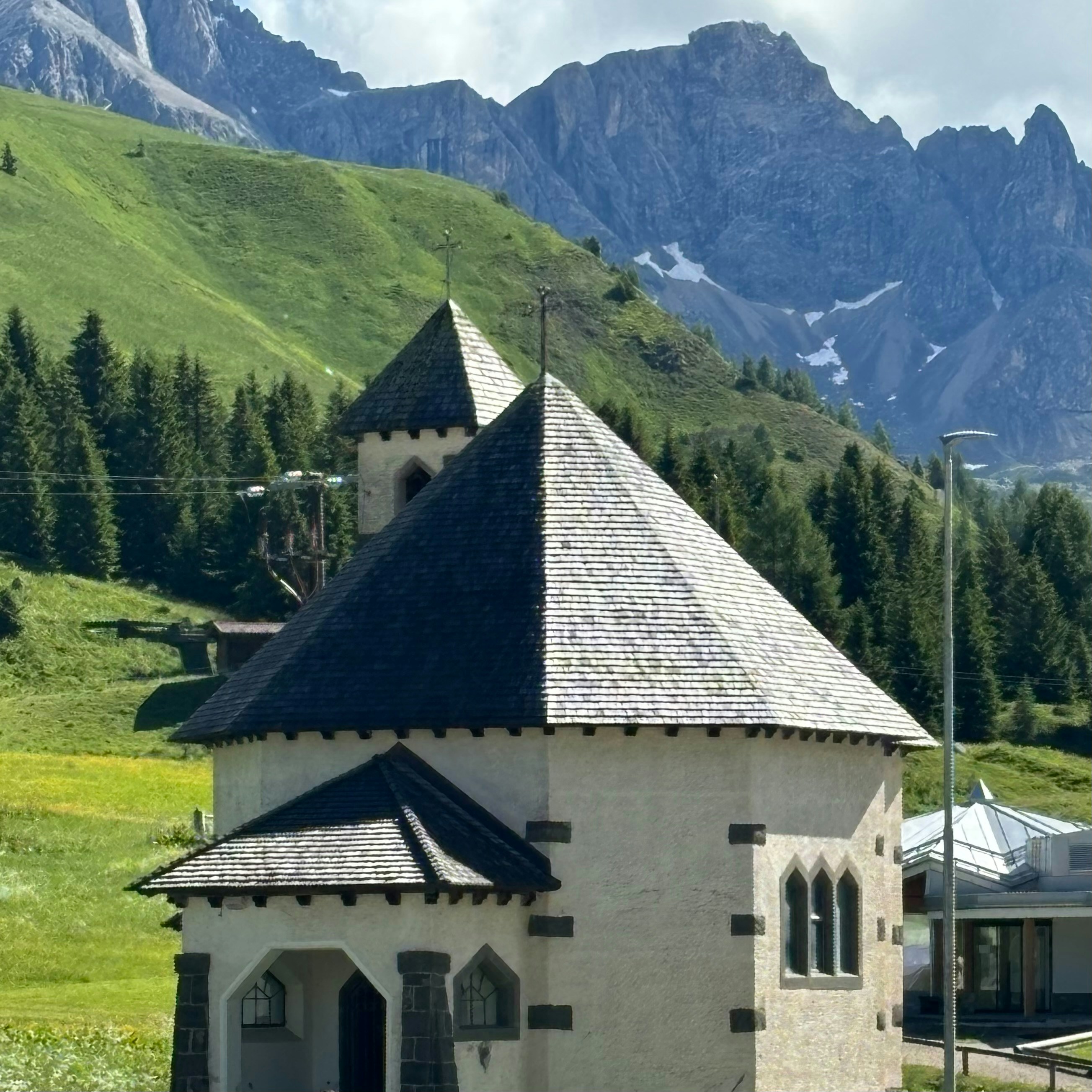 Rustic chalet under alpine peaks with a stone tower roof