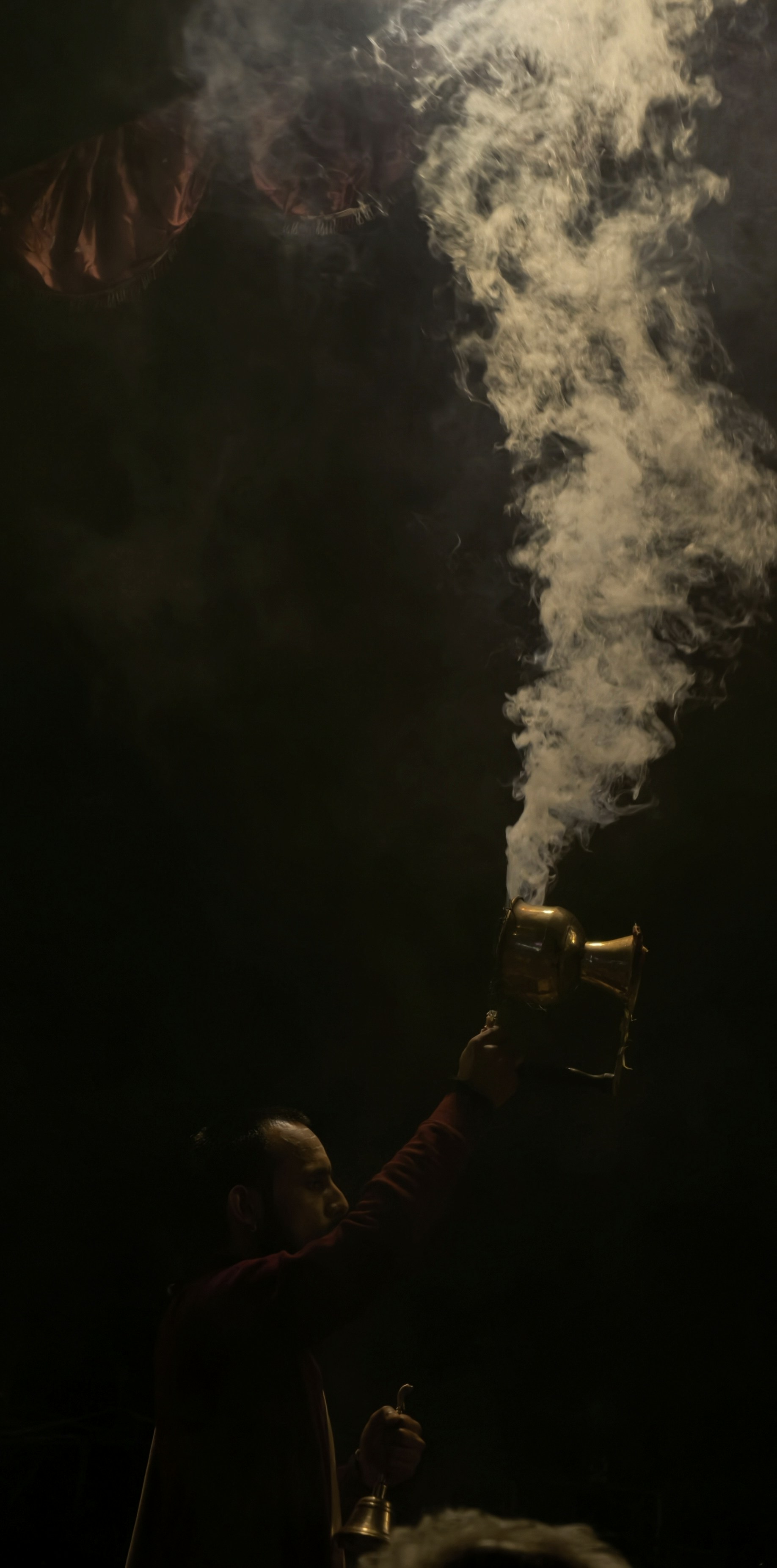 A solitary bell ringer unleashes a plume of smoke against a dark night