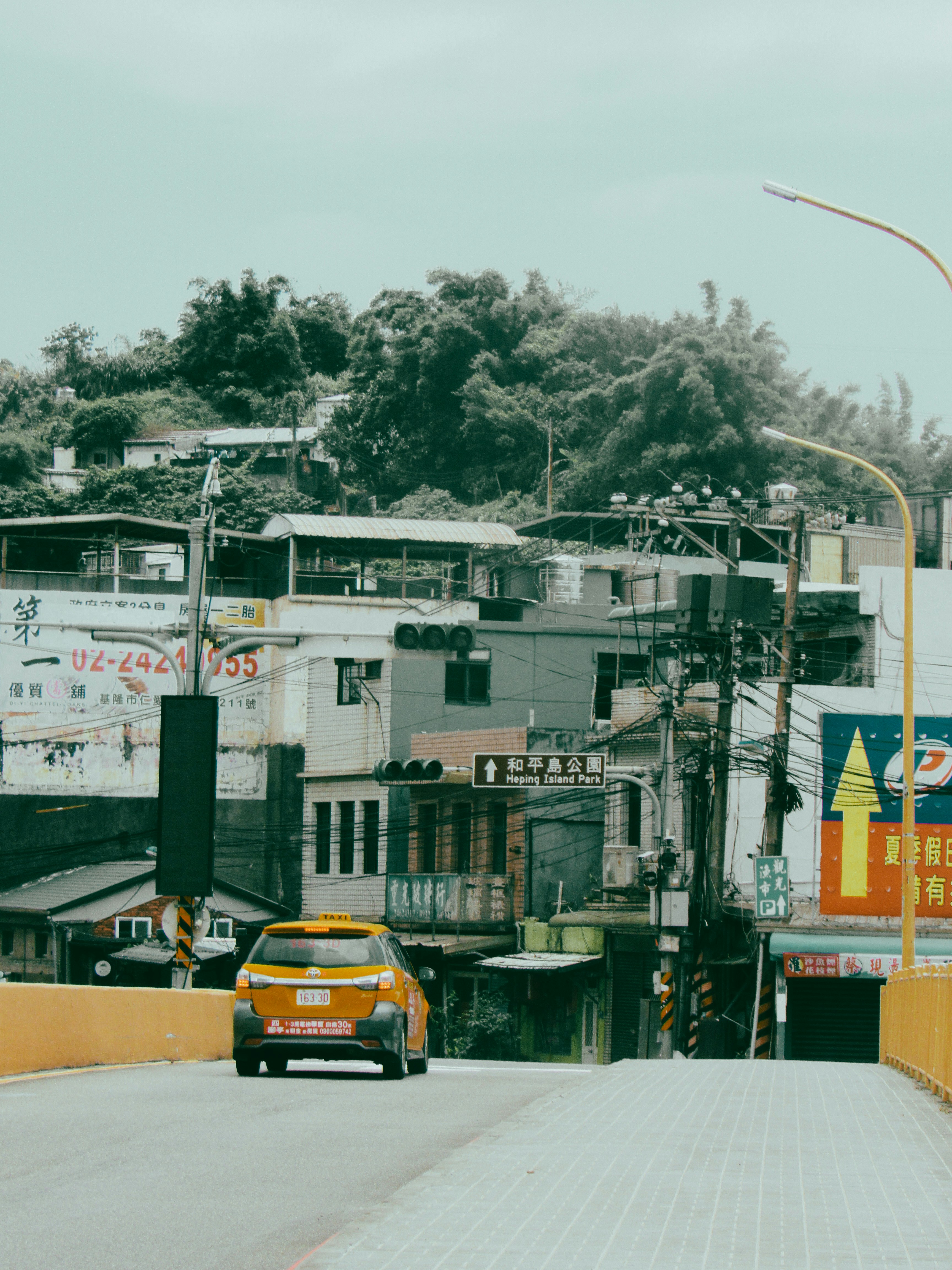 Yellow Taxi on a Concrete Bridge Surrounded by Urban Flora