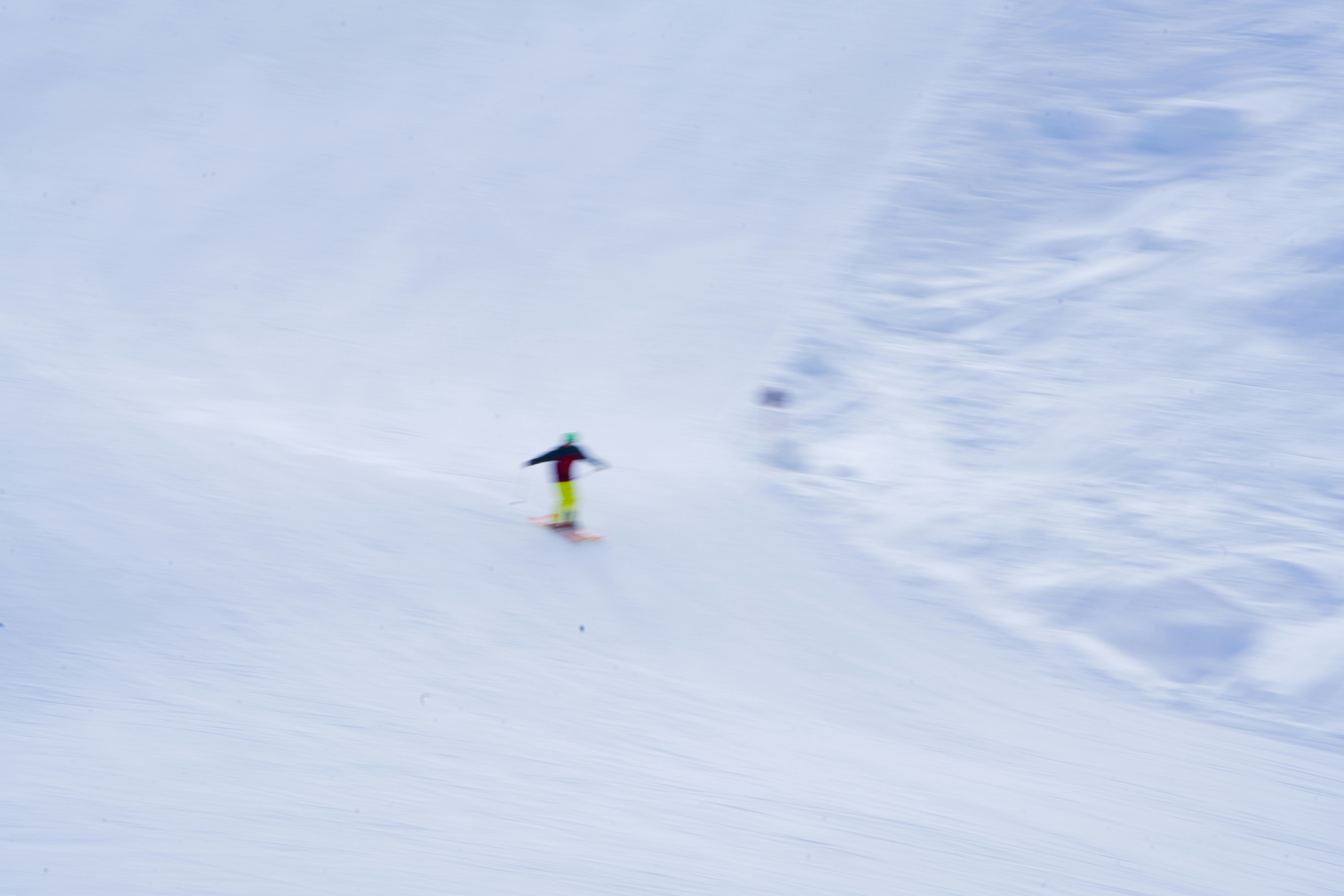 Ghost of the Slopes: A lone skier carving through pale blue silence