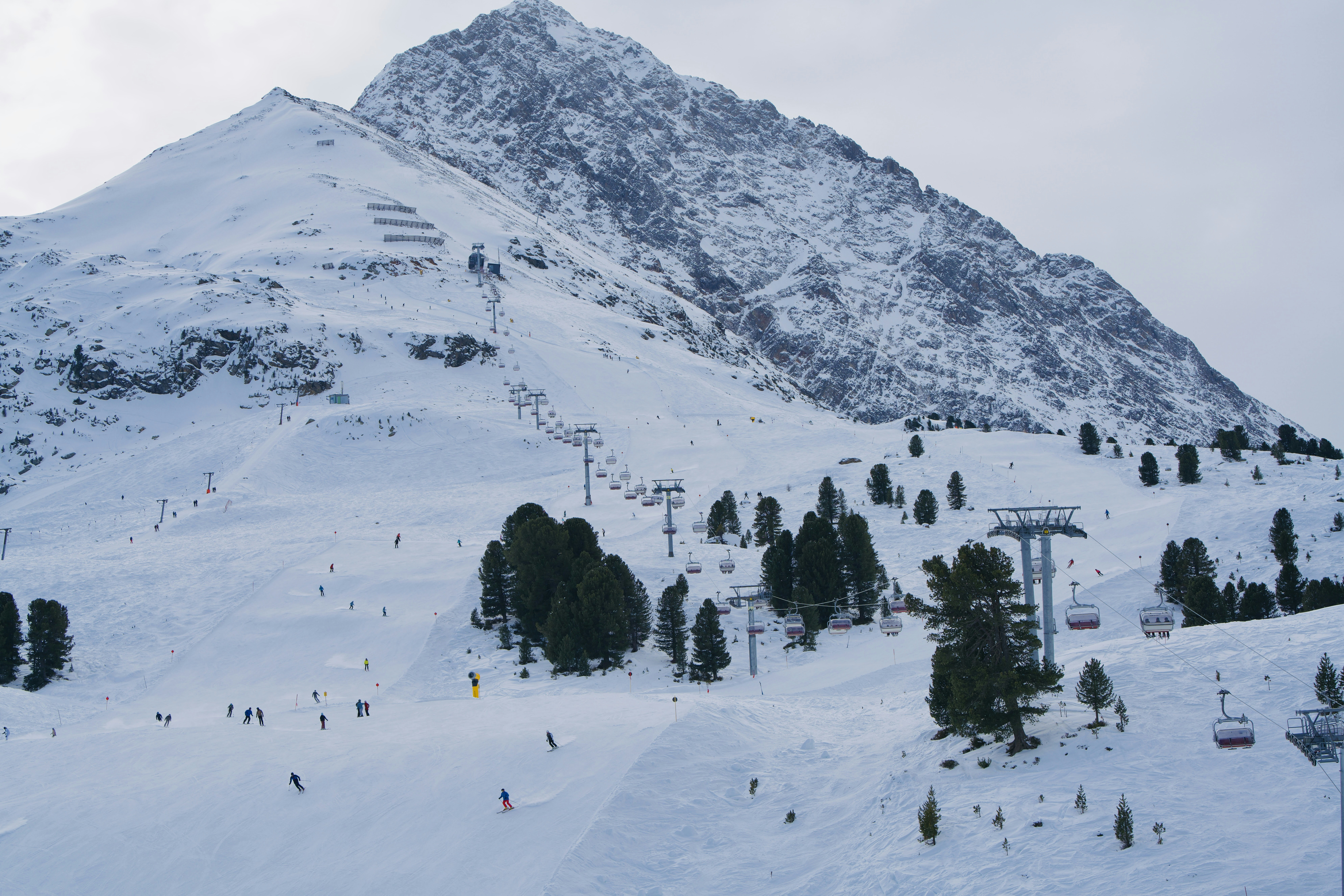 Snowbound Summit: Skier Lifts and Aerial Ropeway Beneath a Steep Peak
