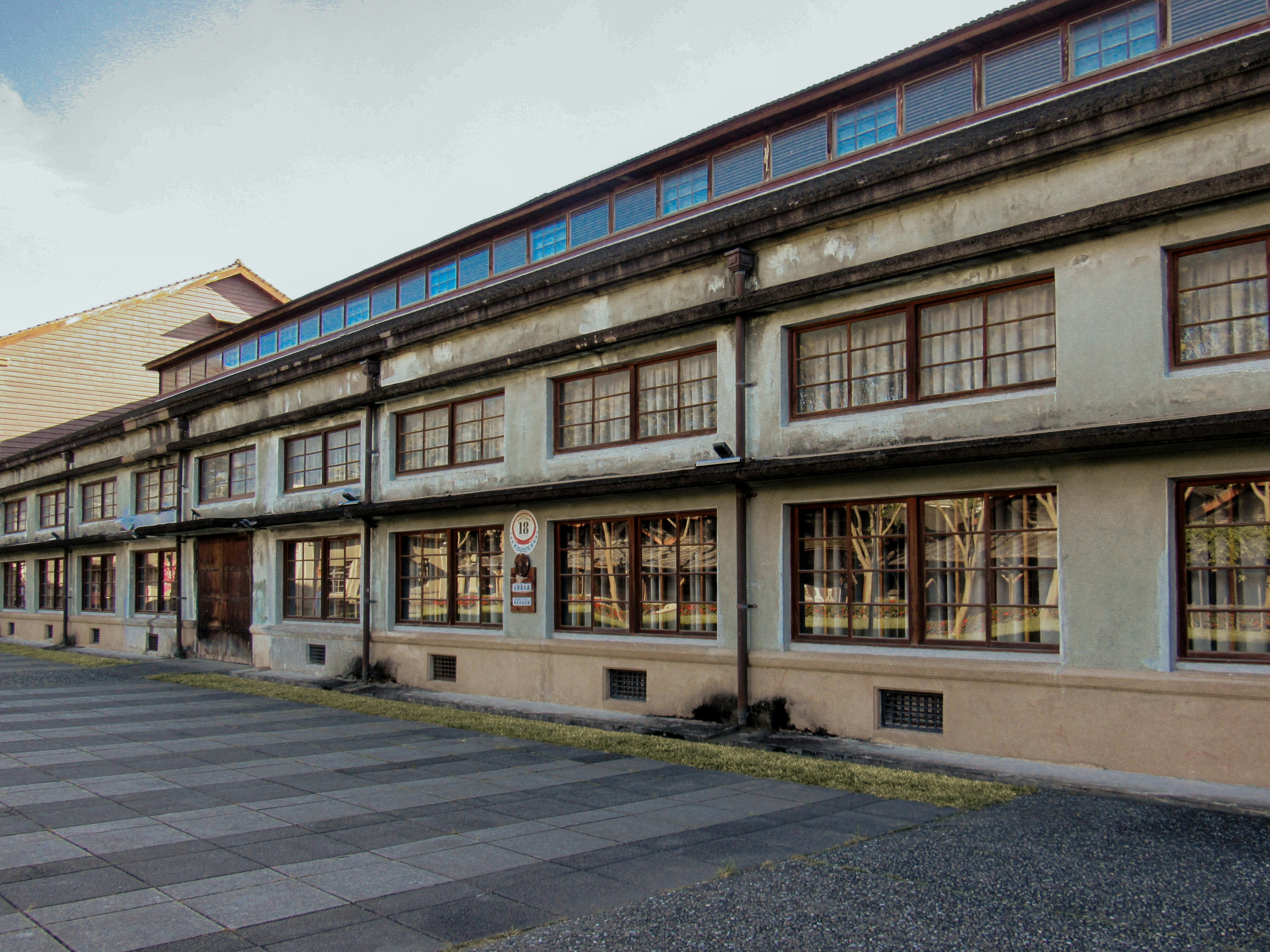 Long, old building with many windows and checkered pavement.