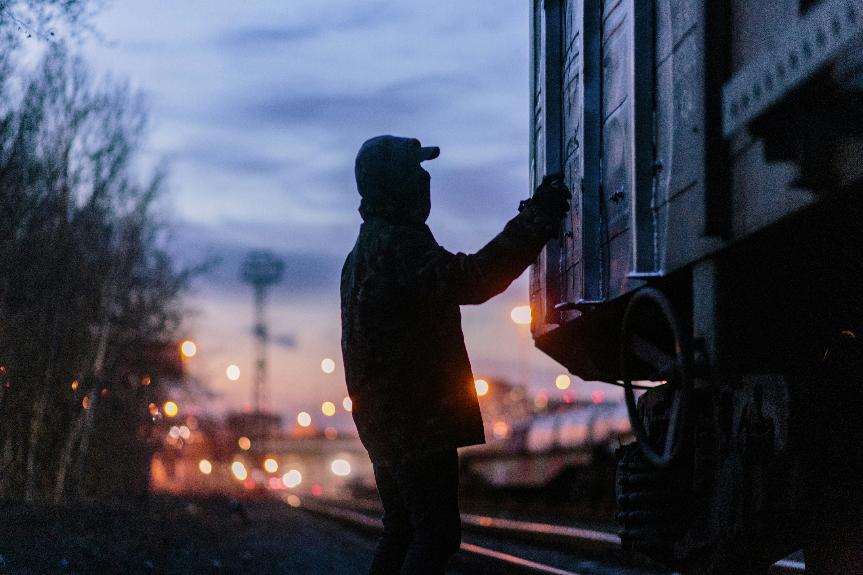Silhouette at Sunset: Worker Grasping a Train Car Door