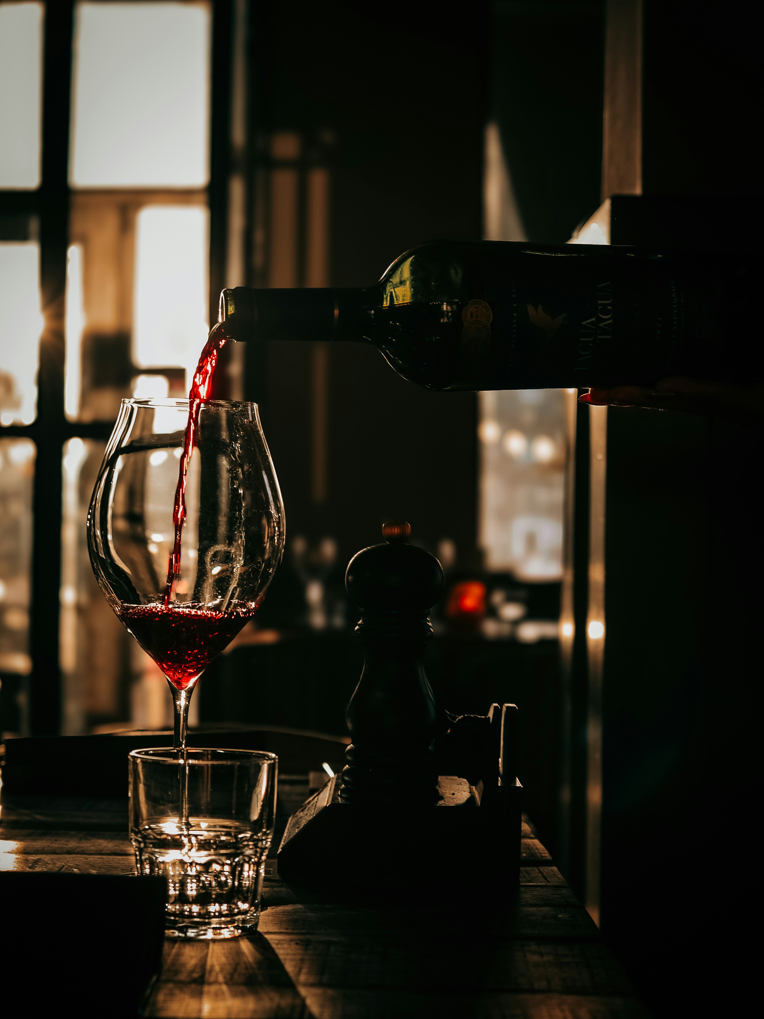 Wine pours into a dimly lit glass: a quiet bar scene in amber light