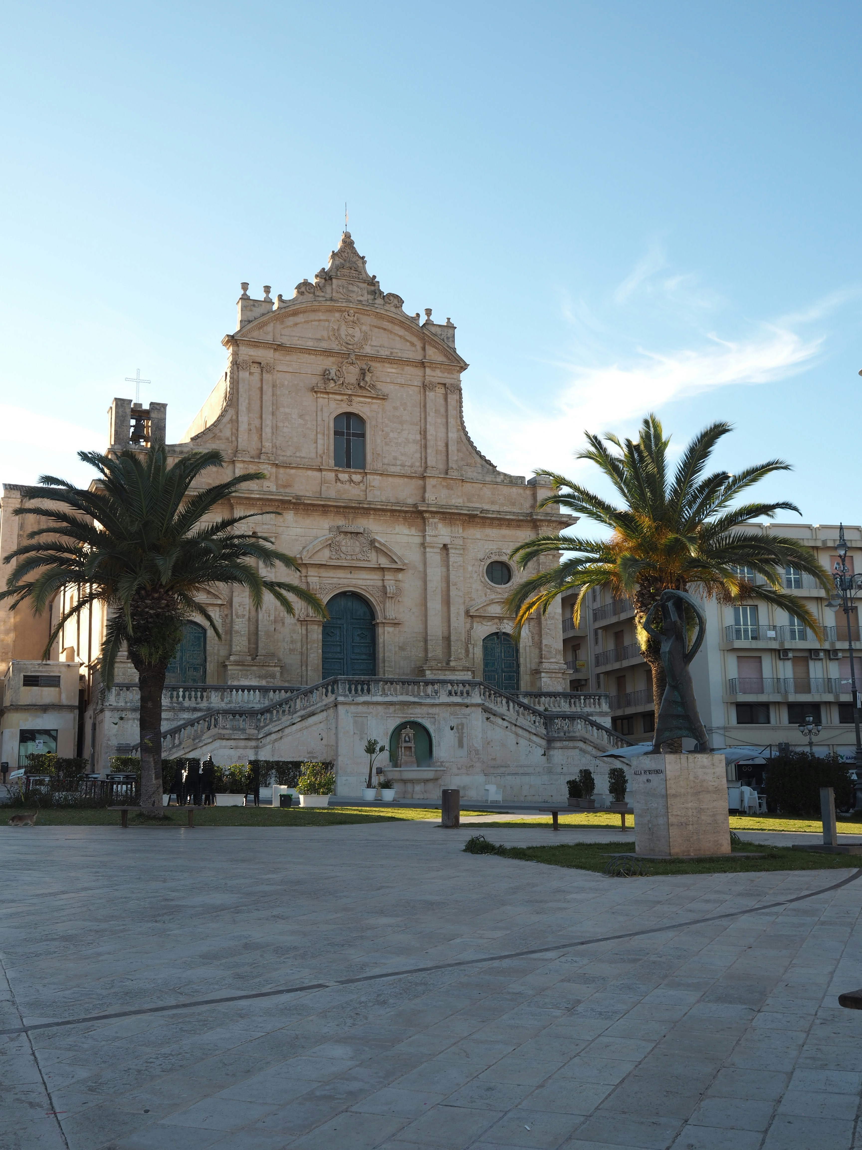 Sunlit Baroque Facade of a Coastal Church Framed by Palm Trees