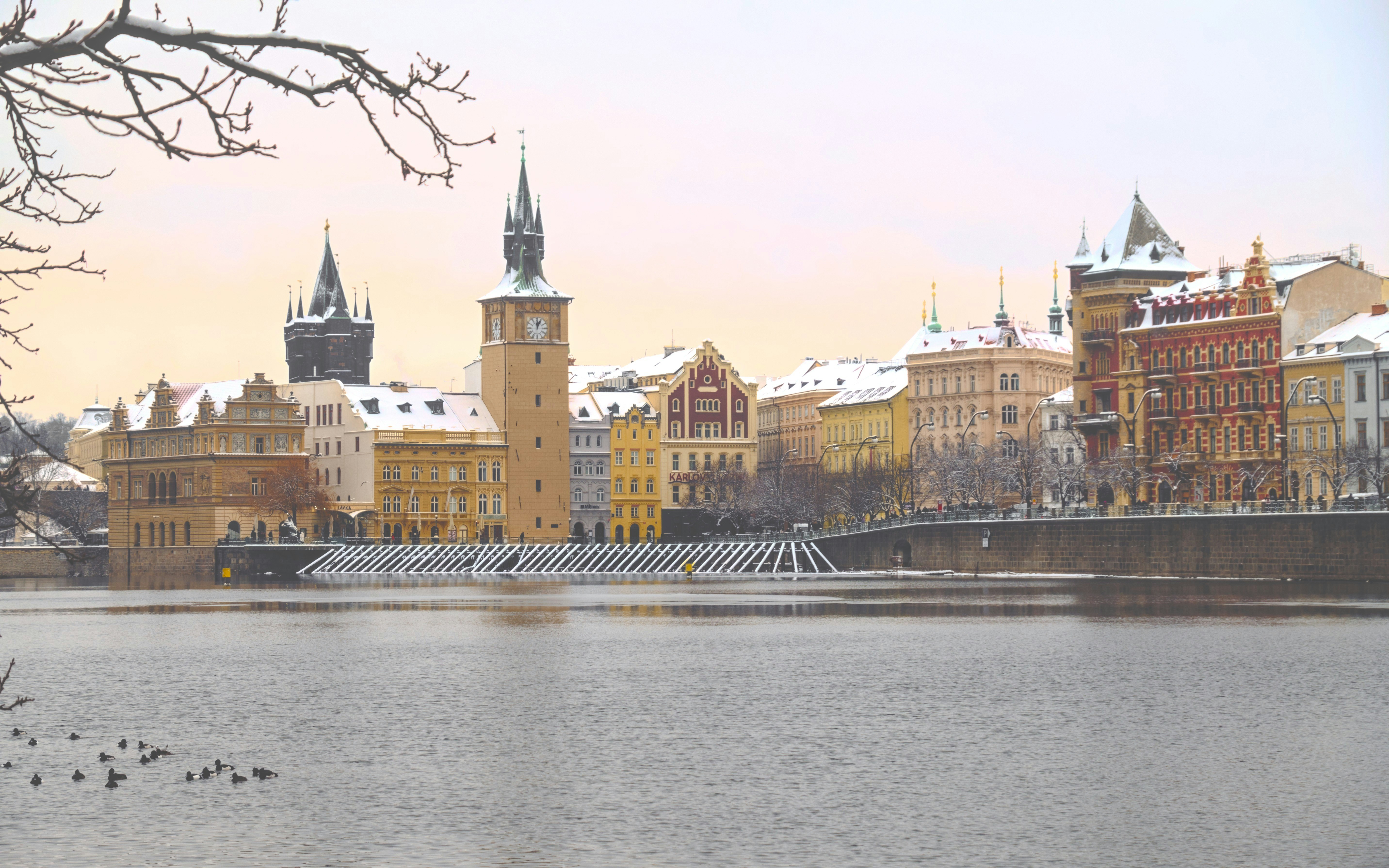 Snow-covered buildings line a river in prague
