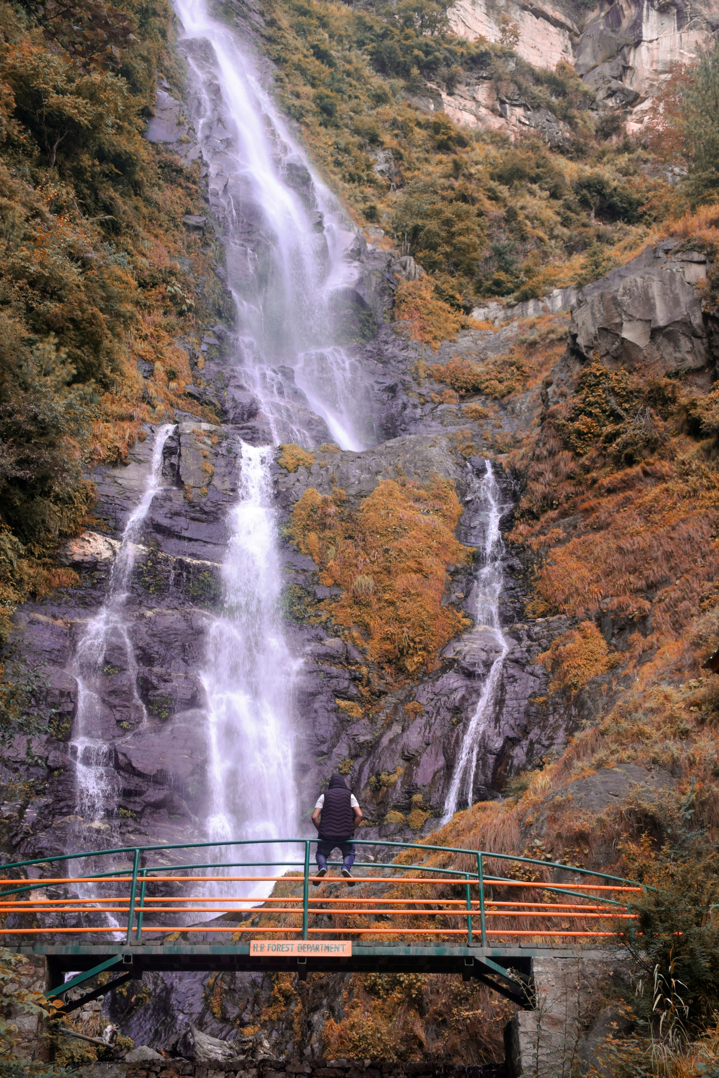 Waterfall Overlook: A lone observer on the railing amid autumn cascades