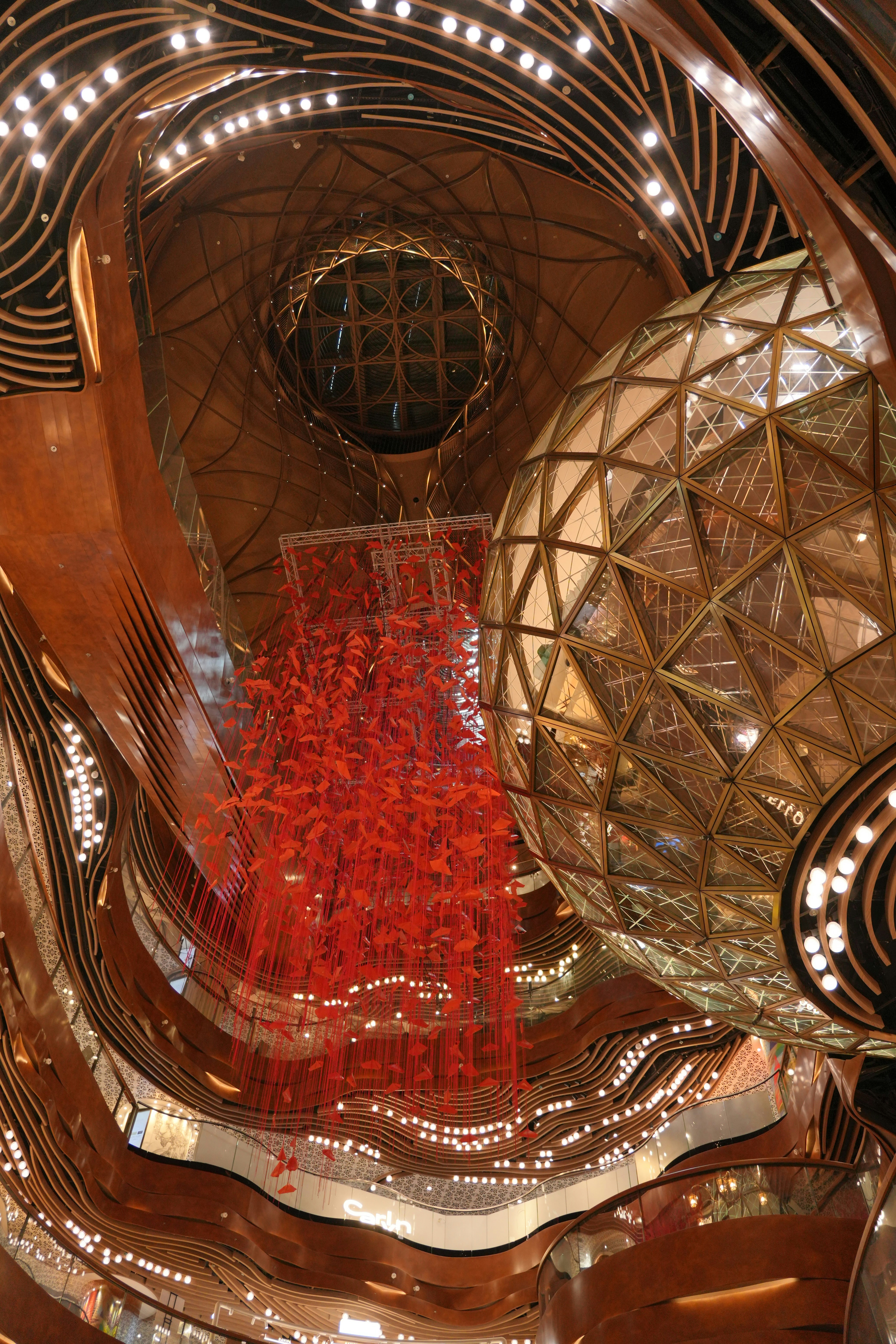 Red Hanging Installation Amidst Metallic Spirals in a Futuristic Atrium