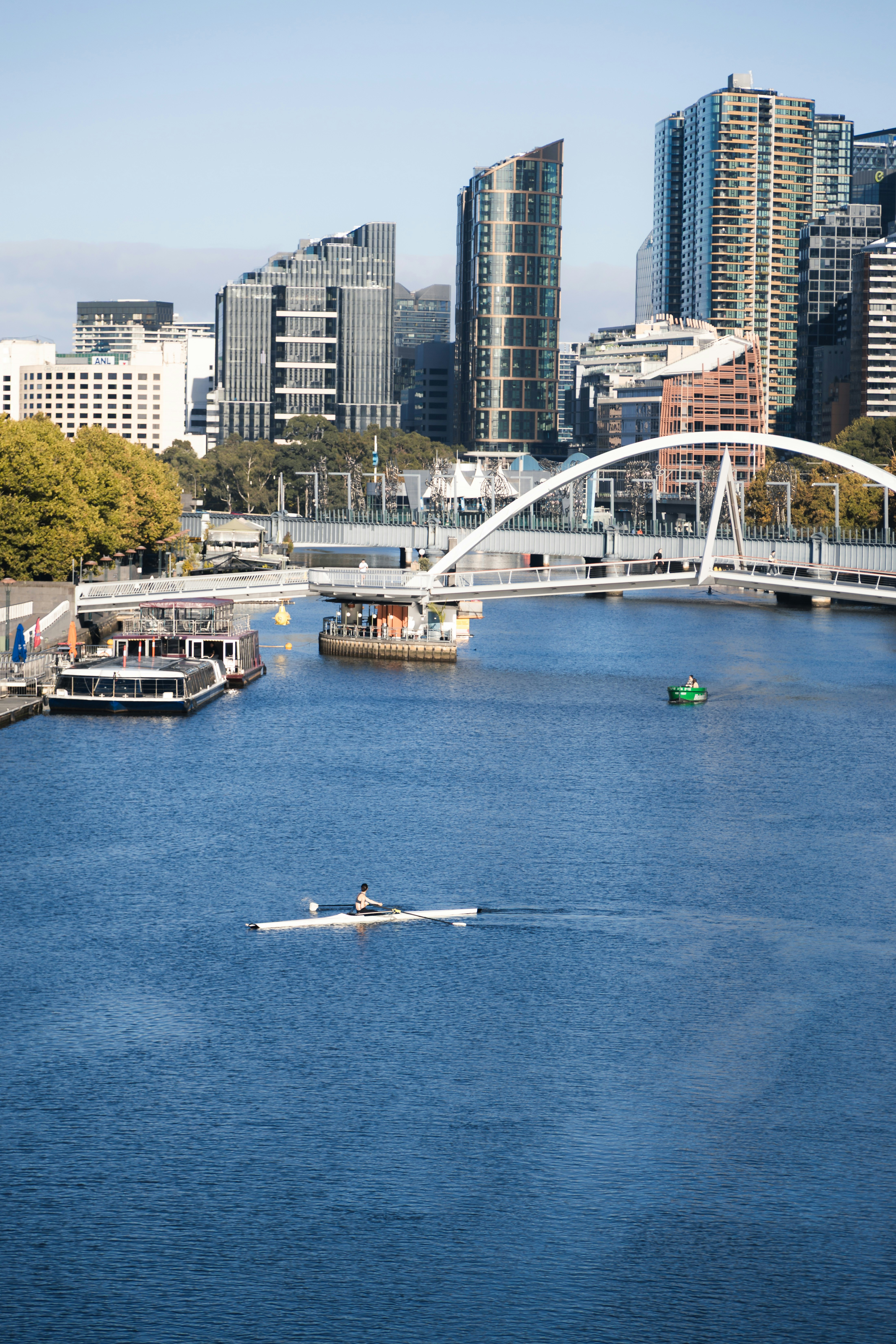 Riverside Skyline: Cityscape and Rowing on a Calm Channel