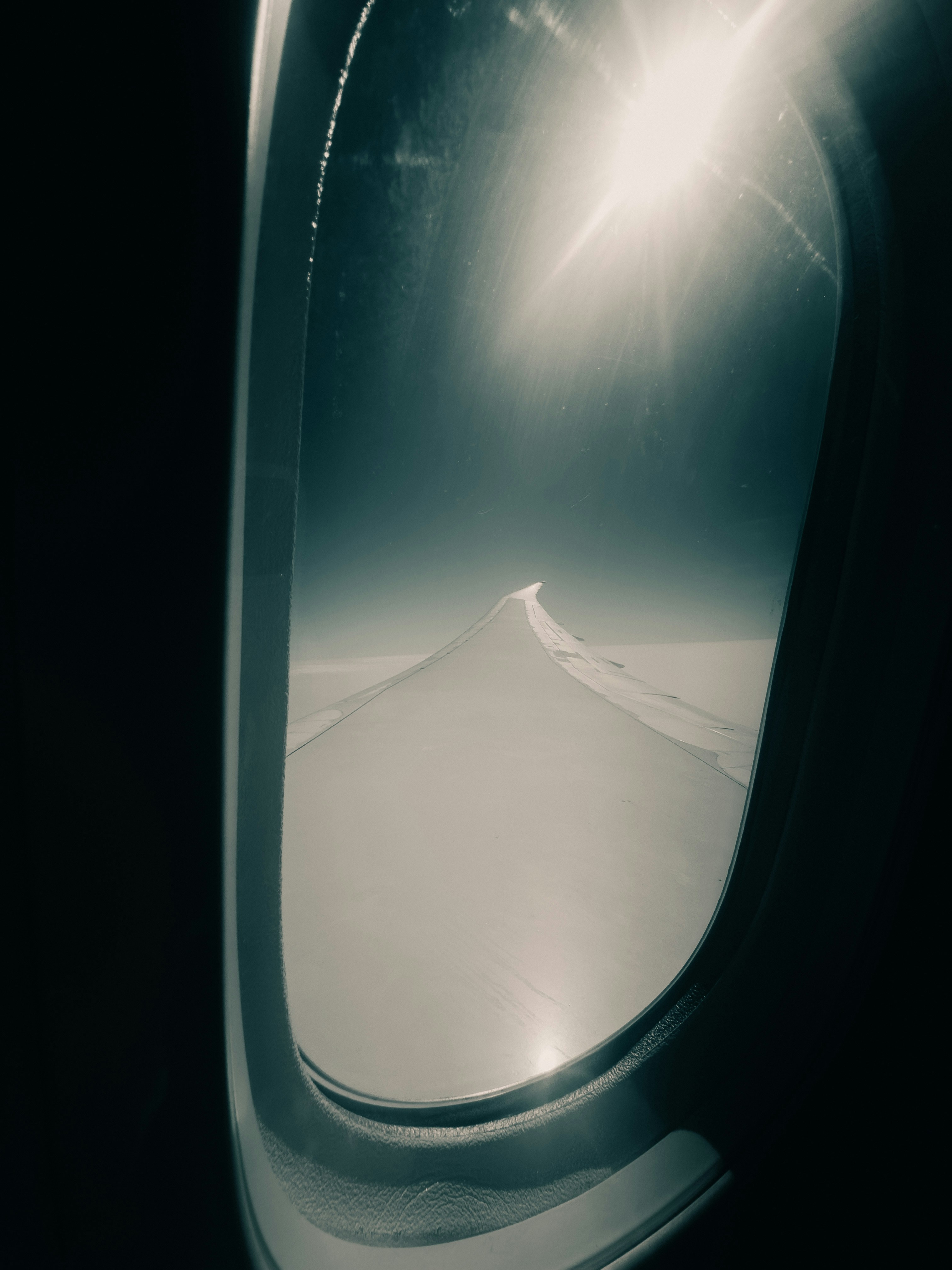 Winged horizon: the aircraft window freezes a tip of distant summit