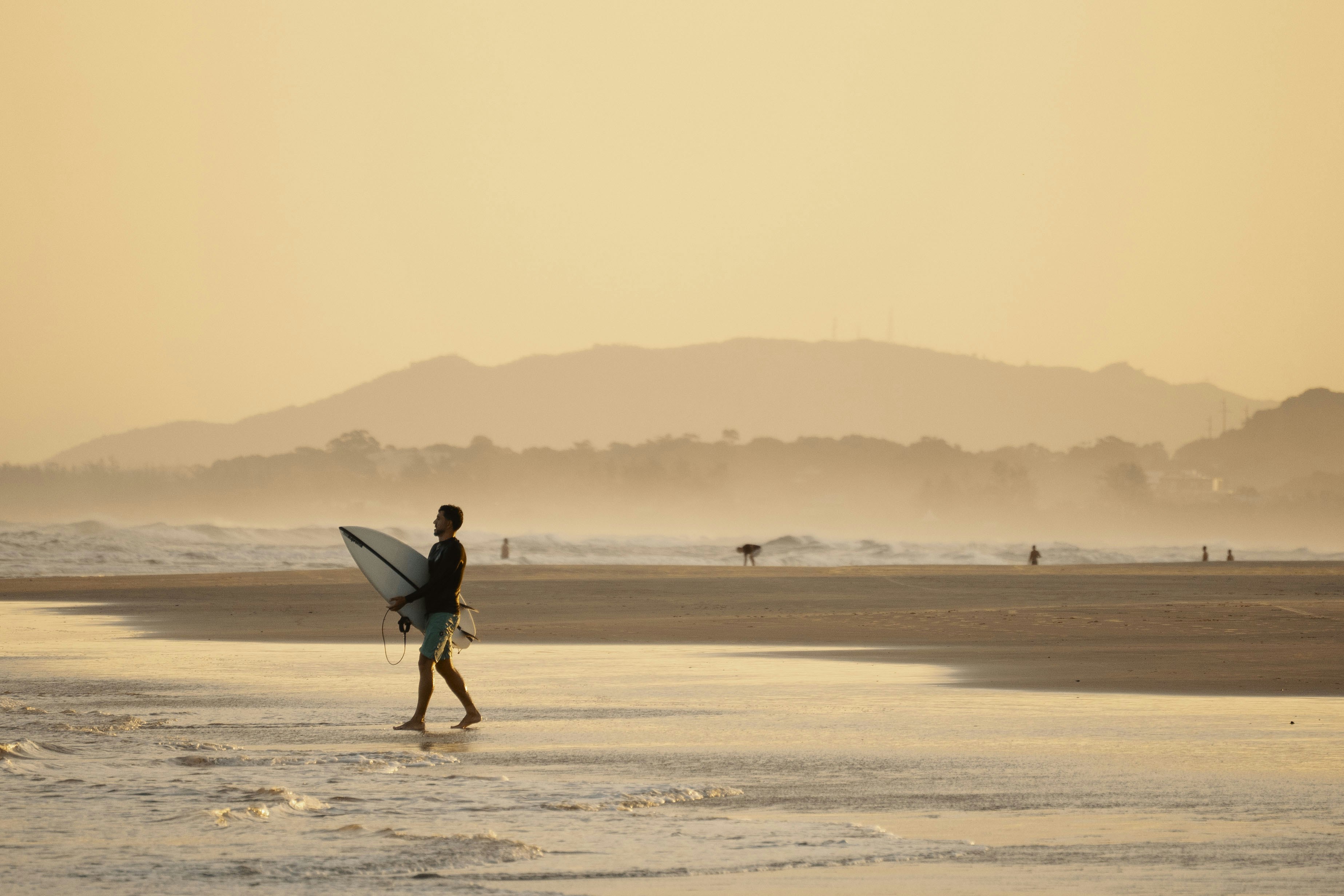 Surfer with a Silhouette Against a Misty Dune Horizon