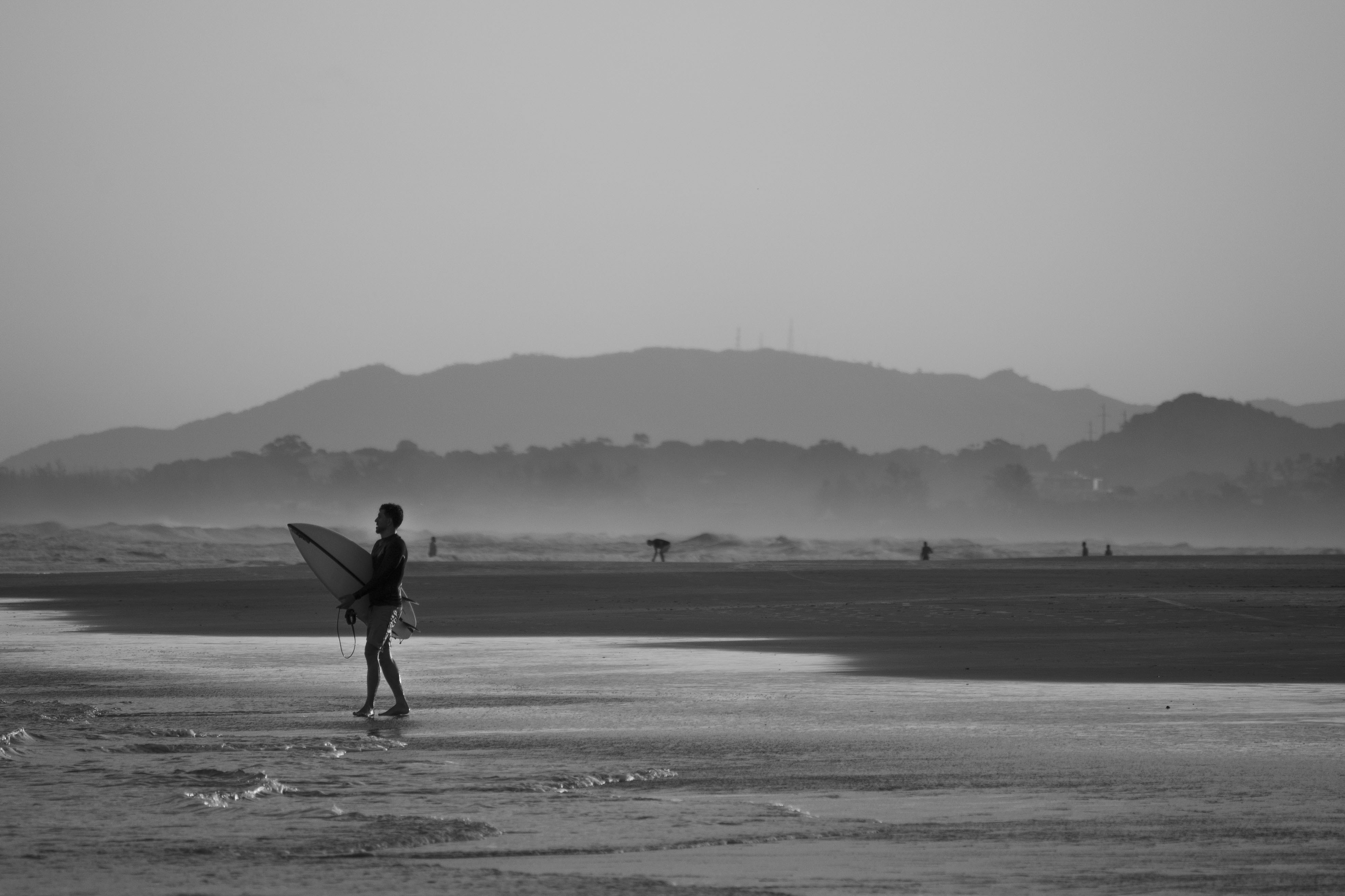 Surf Rider at Low Tide: A solitary silhouette against a misty shoreline