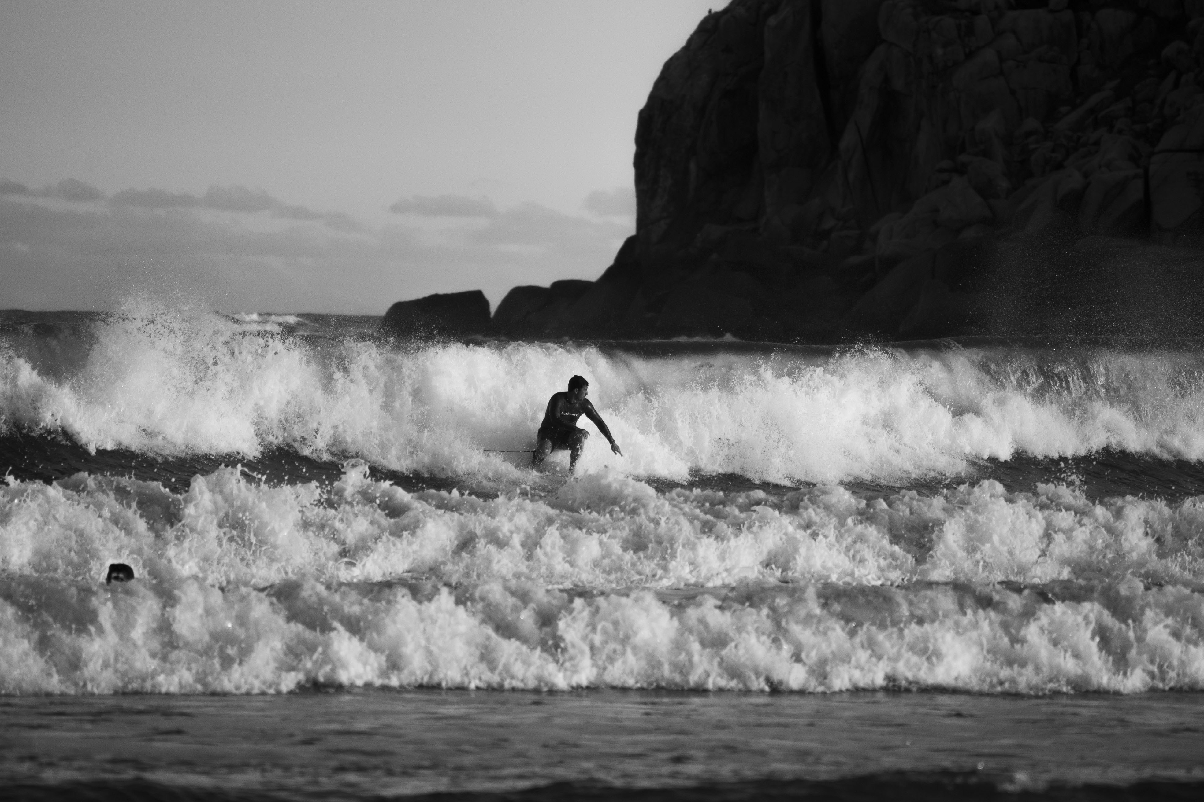 Solitary Surfer Riding a Wall of Foam at Dusk