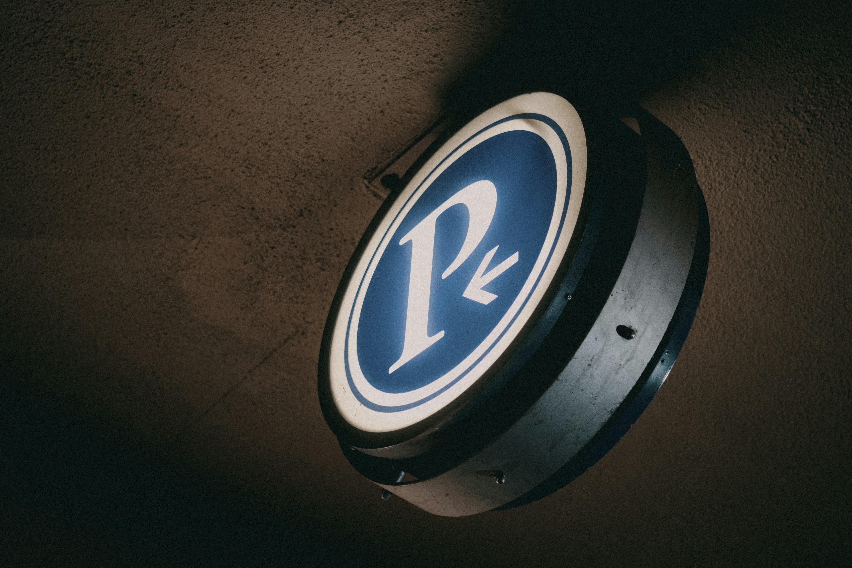 Midnight Sign: A Blue Parking Icon Emerges from Deep Shadow