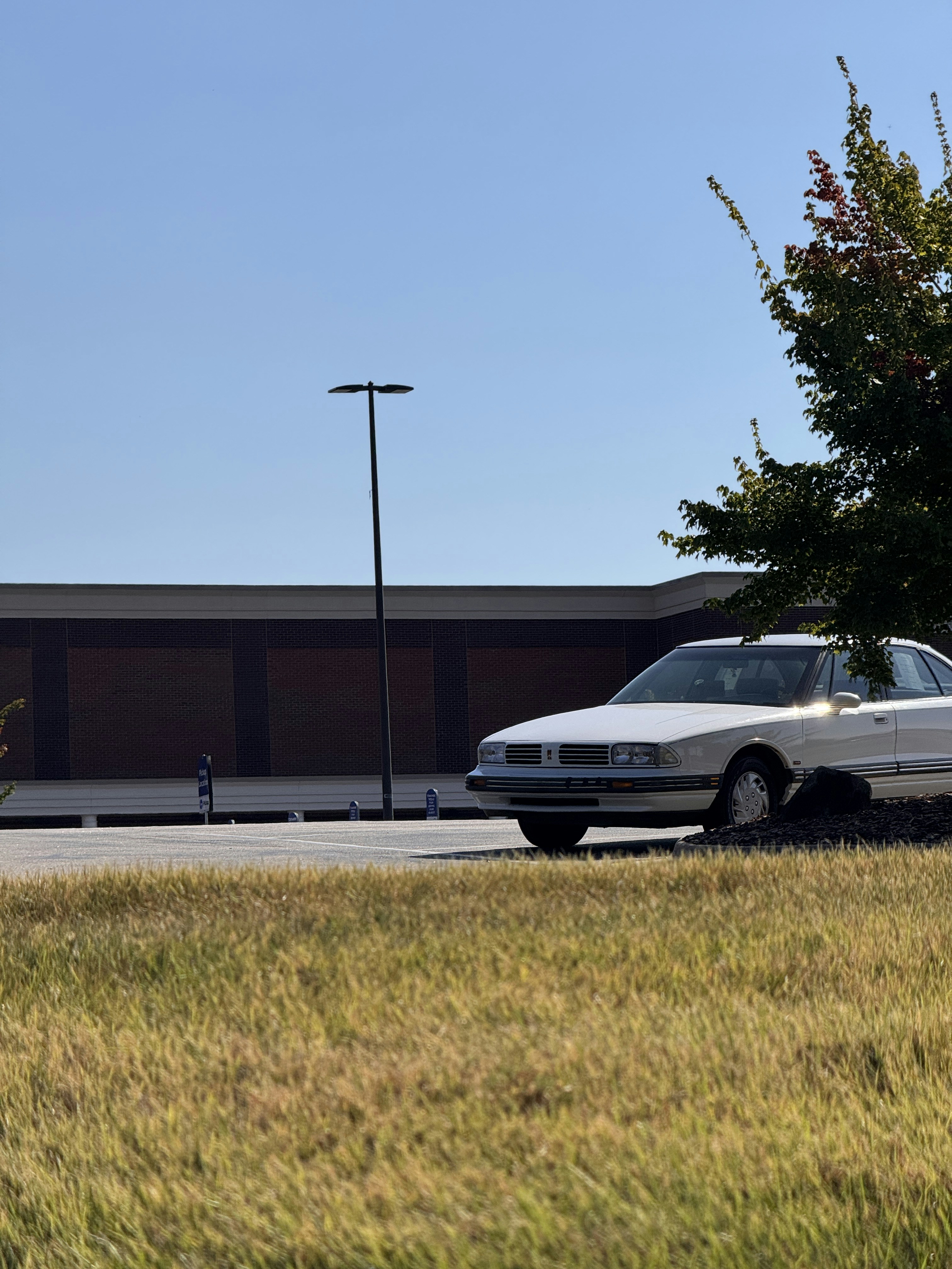 White sedan by the curb under a clear blue sky