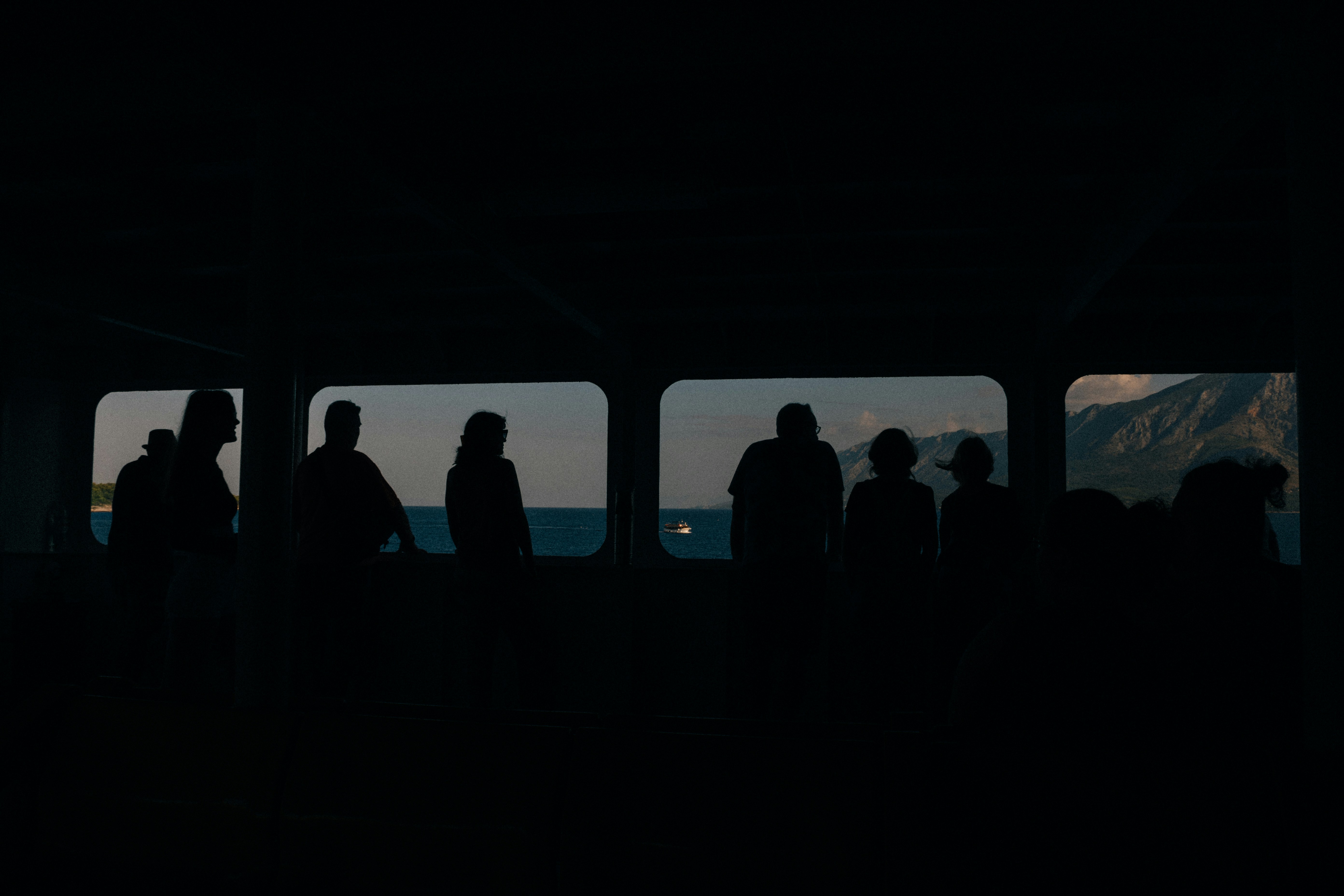Silhouette Corridor: Passengers Framed by Distant Mountain Light