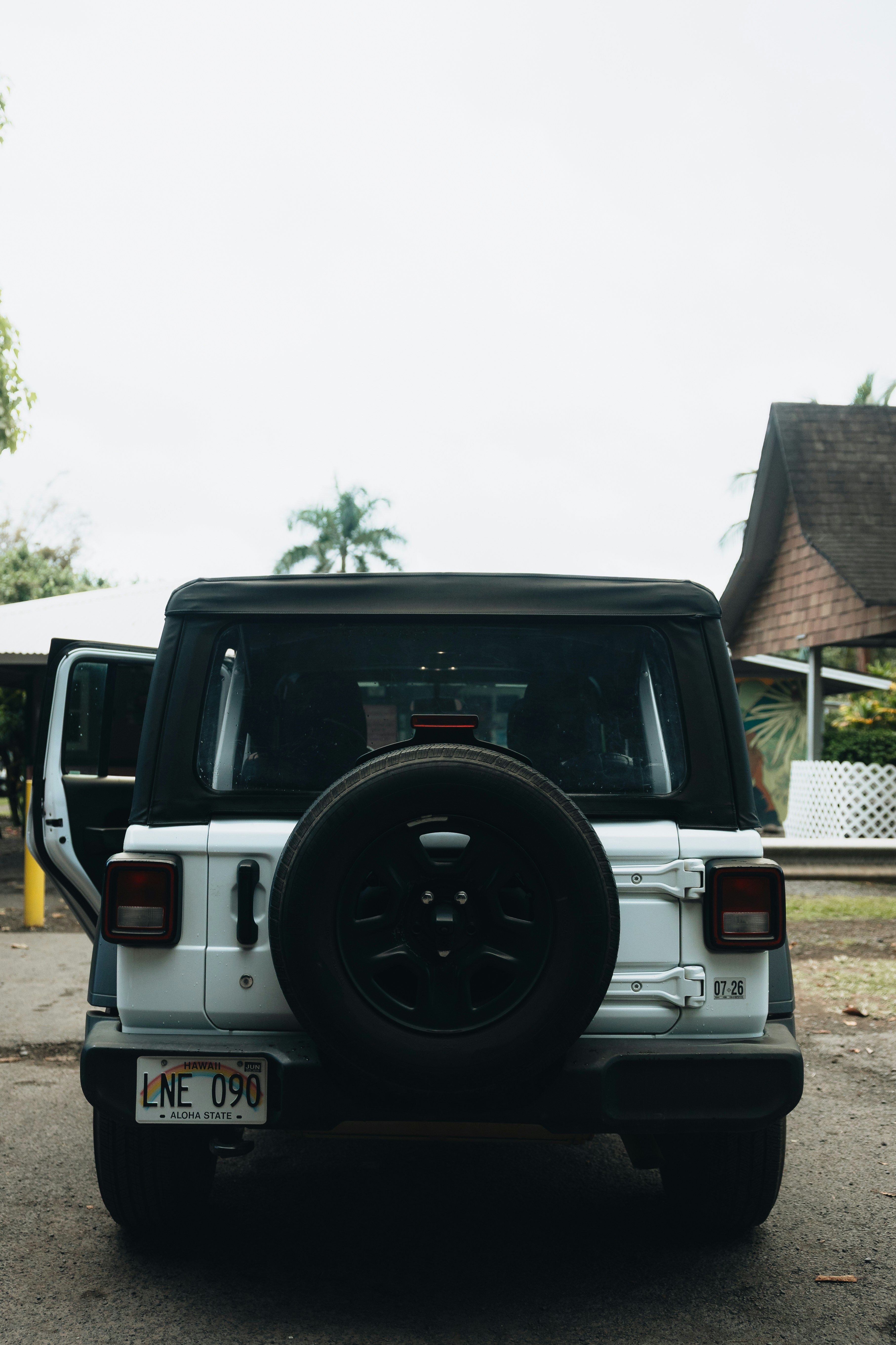 Rear View in a Quiet Parking Lot: A White SUV with a Spared-Tire Portrait