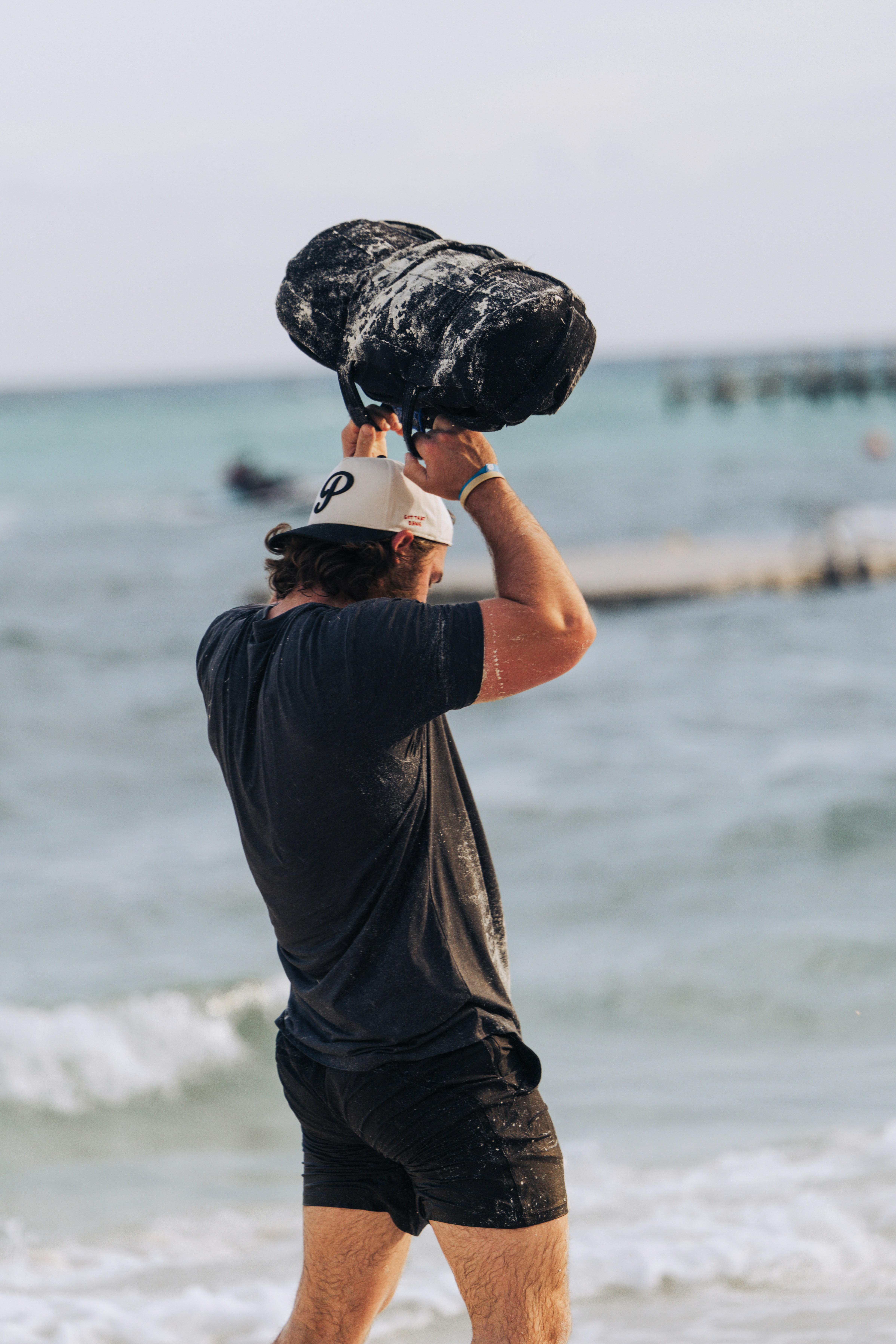 Liftoff on the Beach: A Cameraman Hoists a Weathered Travel Bag