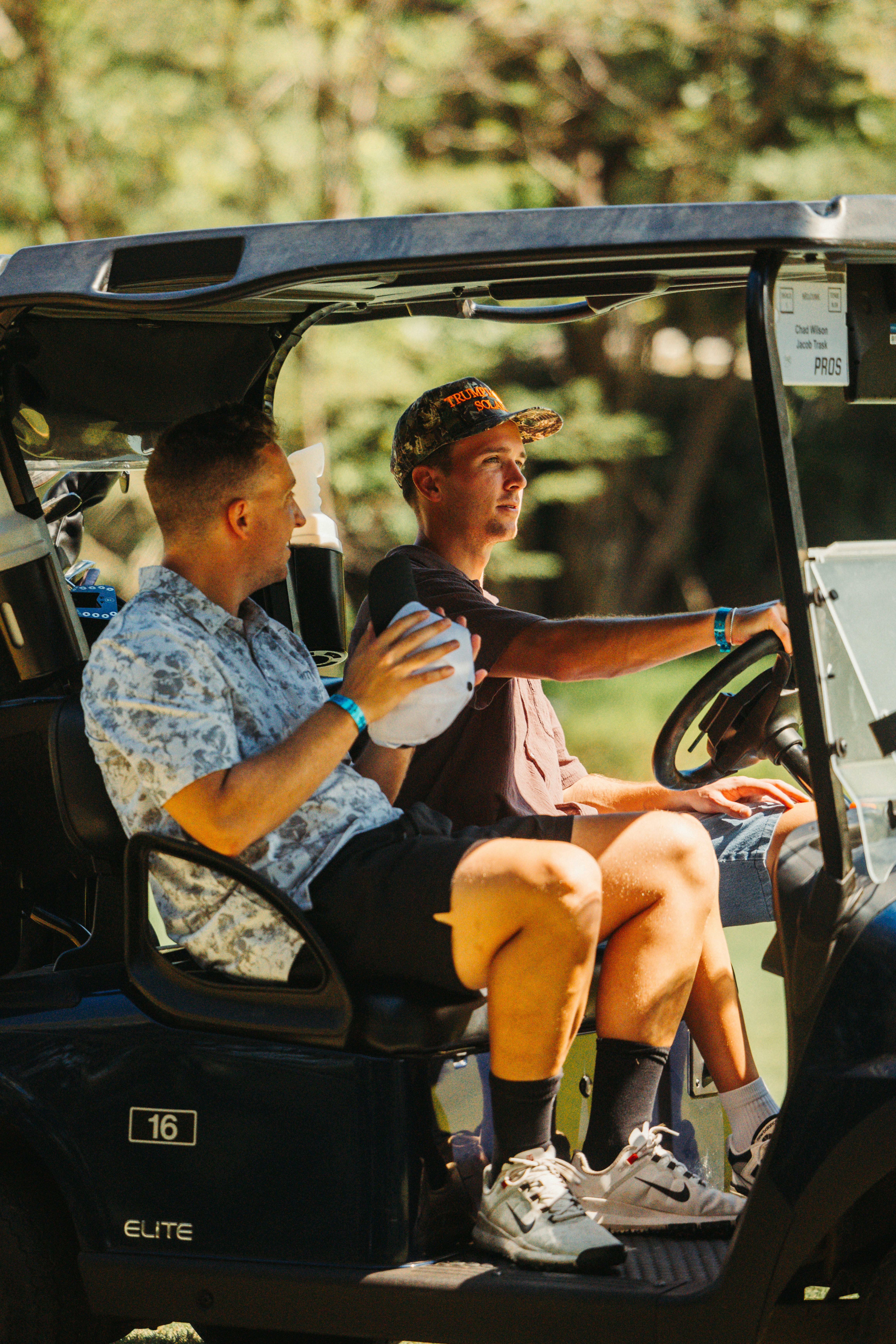 Sunlit Caddie Conversation: Two Friends in a Golf Cart