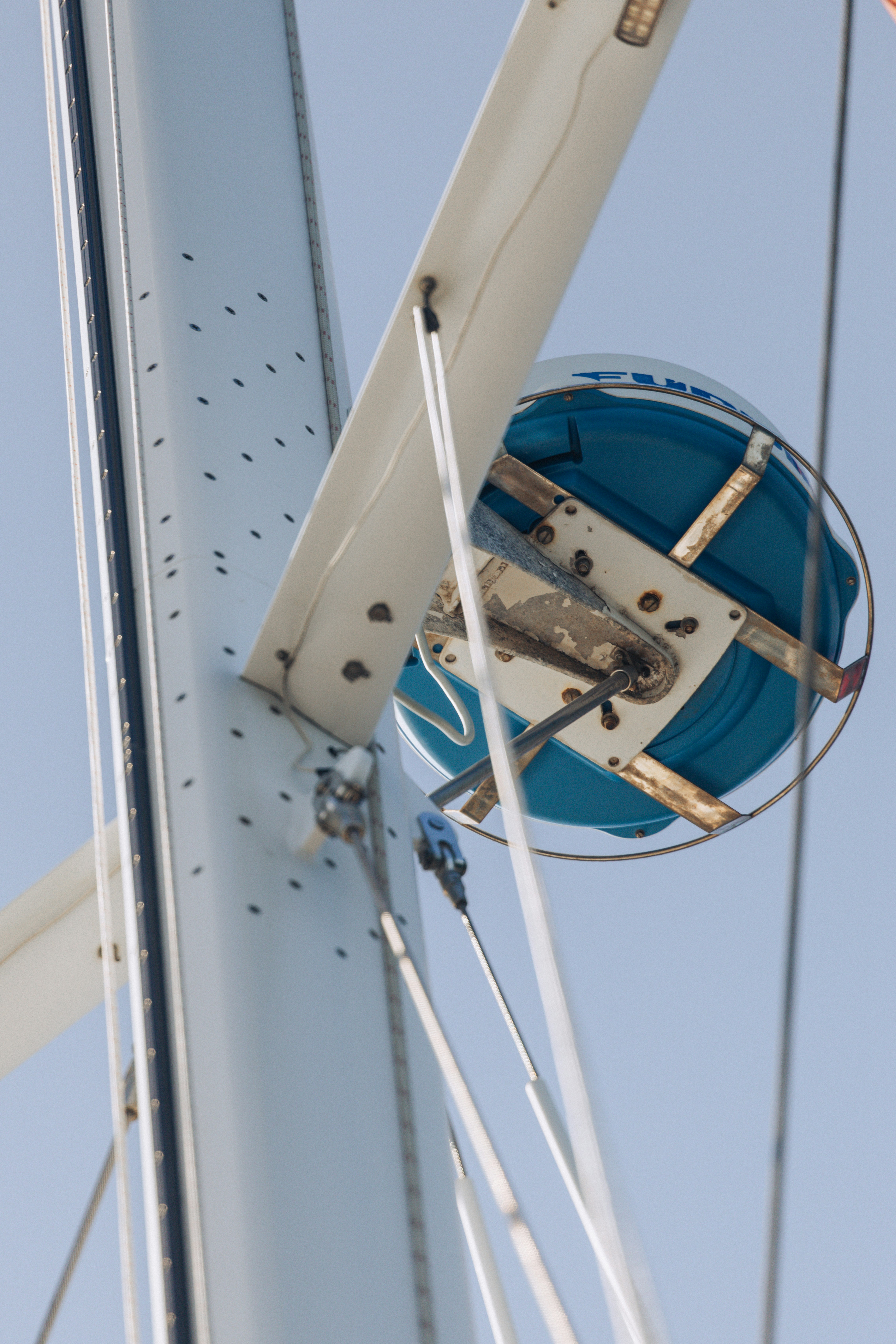 Blue Reel on the Crane: A Close-Up of a Mechanical Pulley System Against Clear Sky