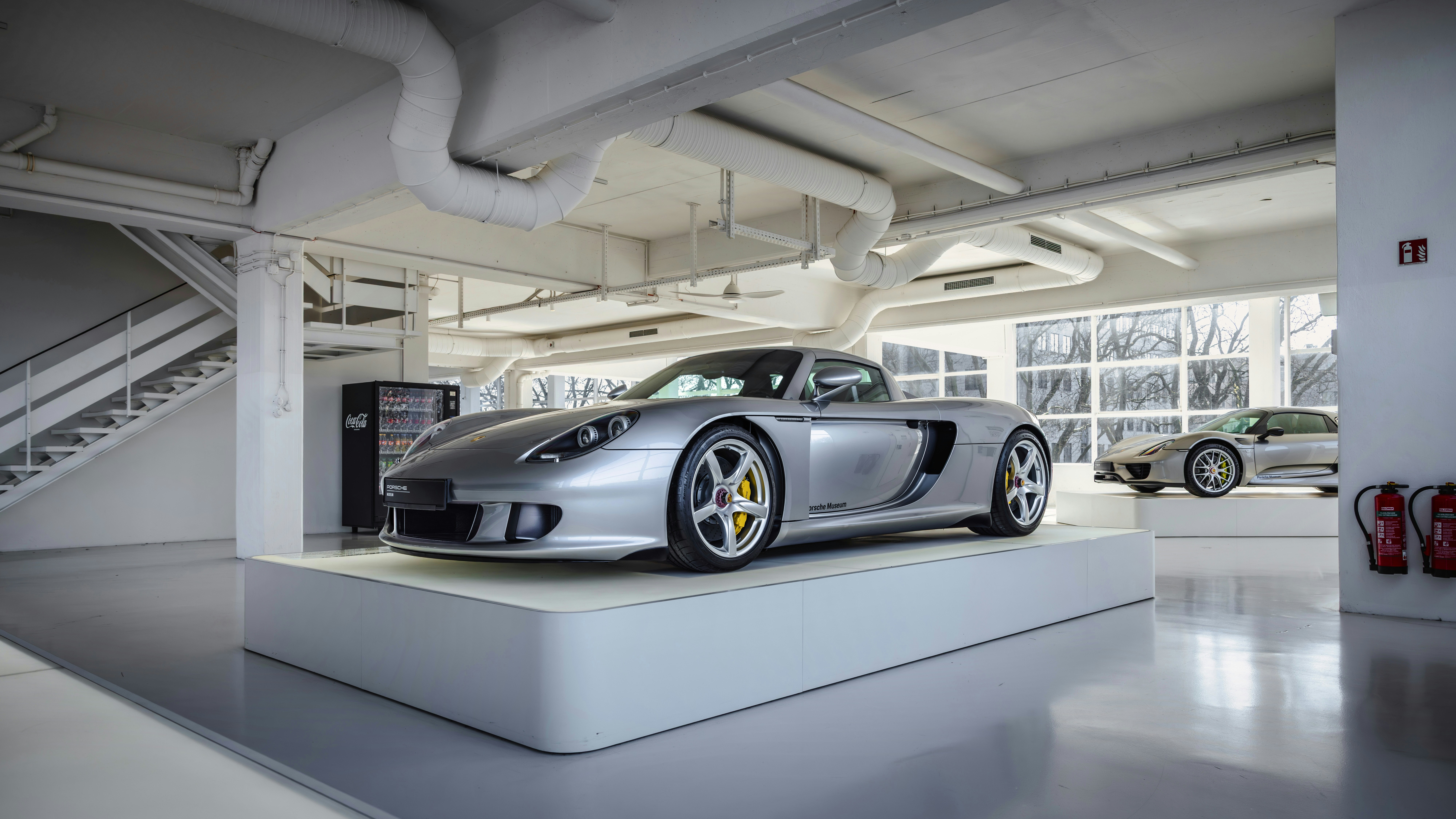 Silver supercar on a display podium in a modern showroom