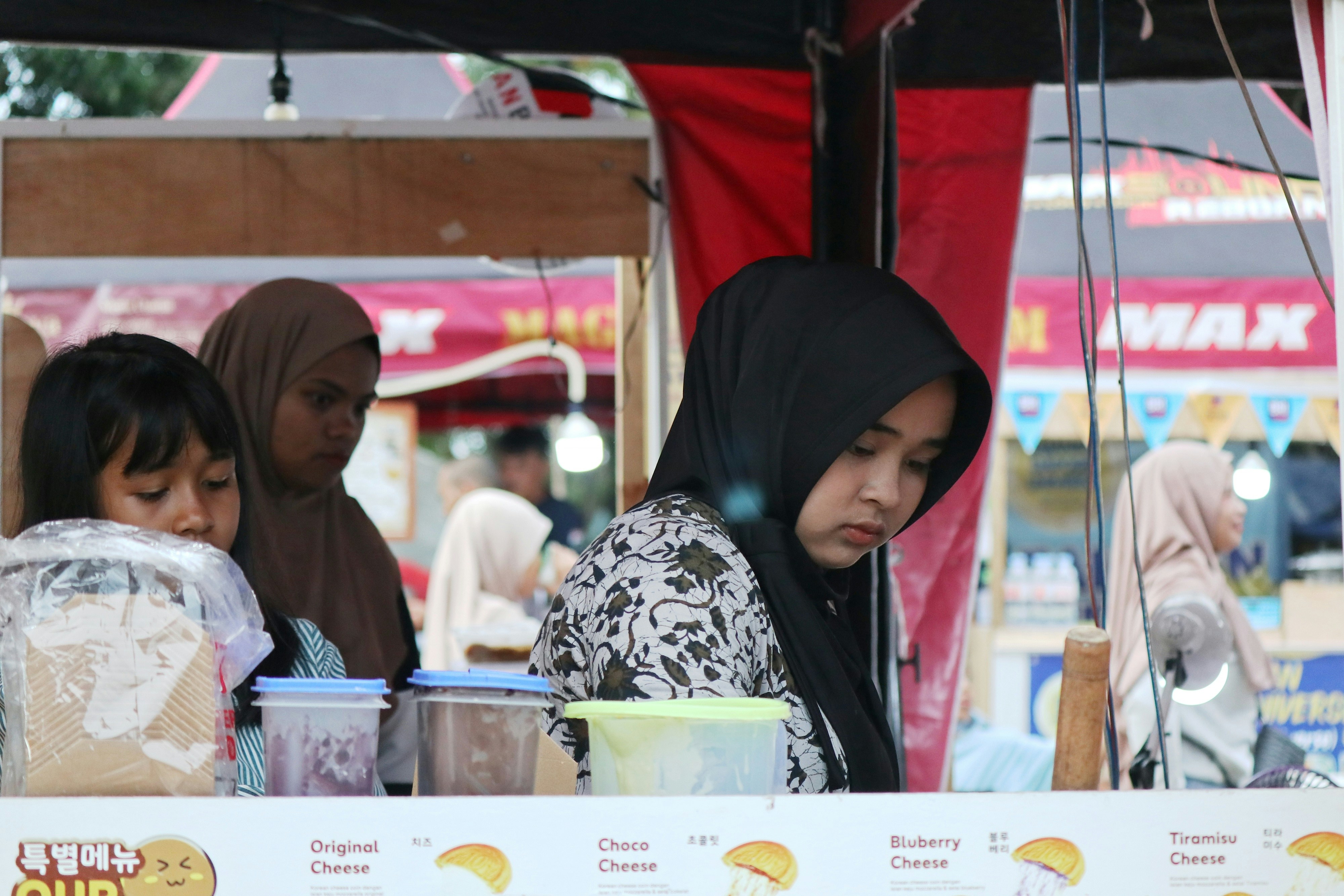 Quiet focus: three young women in hijabs study a market stall