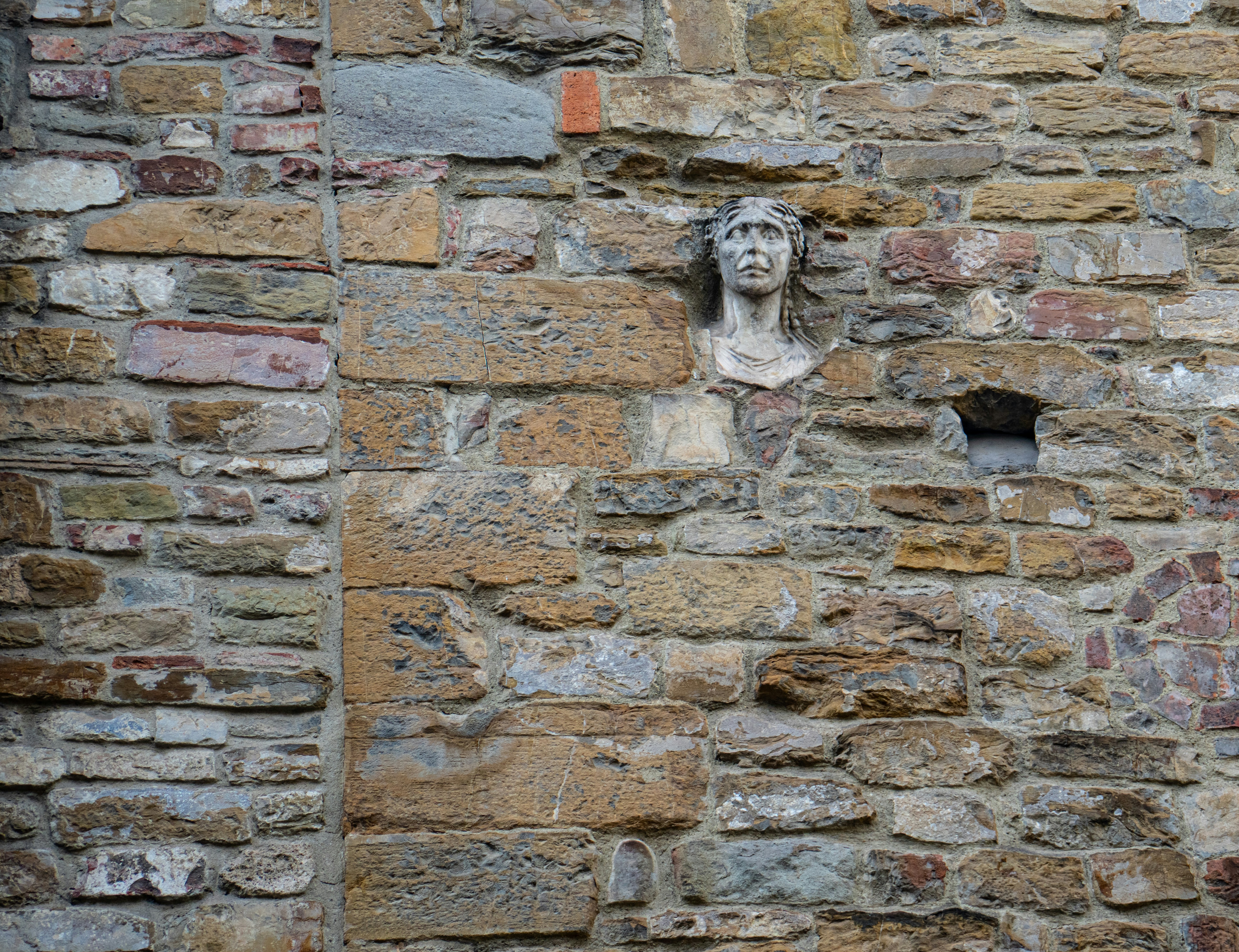 Stone-face Guardian: A Weathered Carving Emerges from the Wall