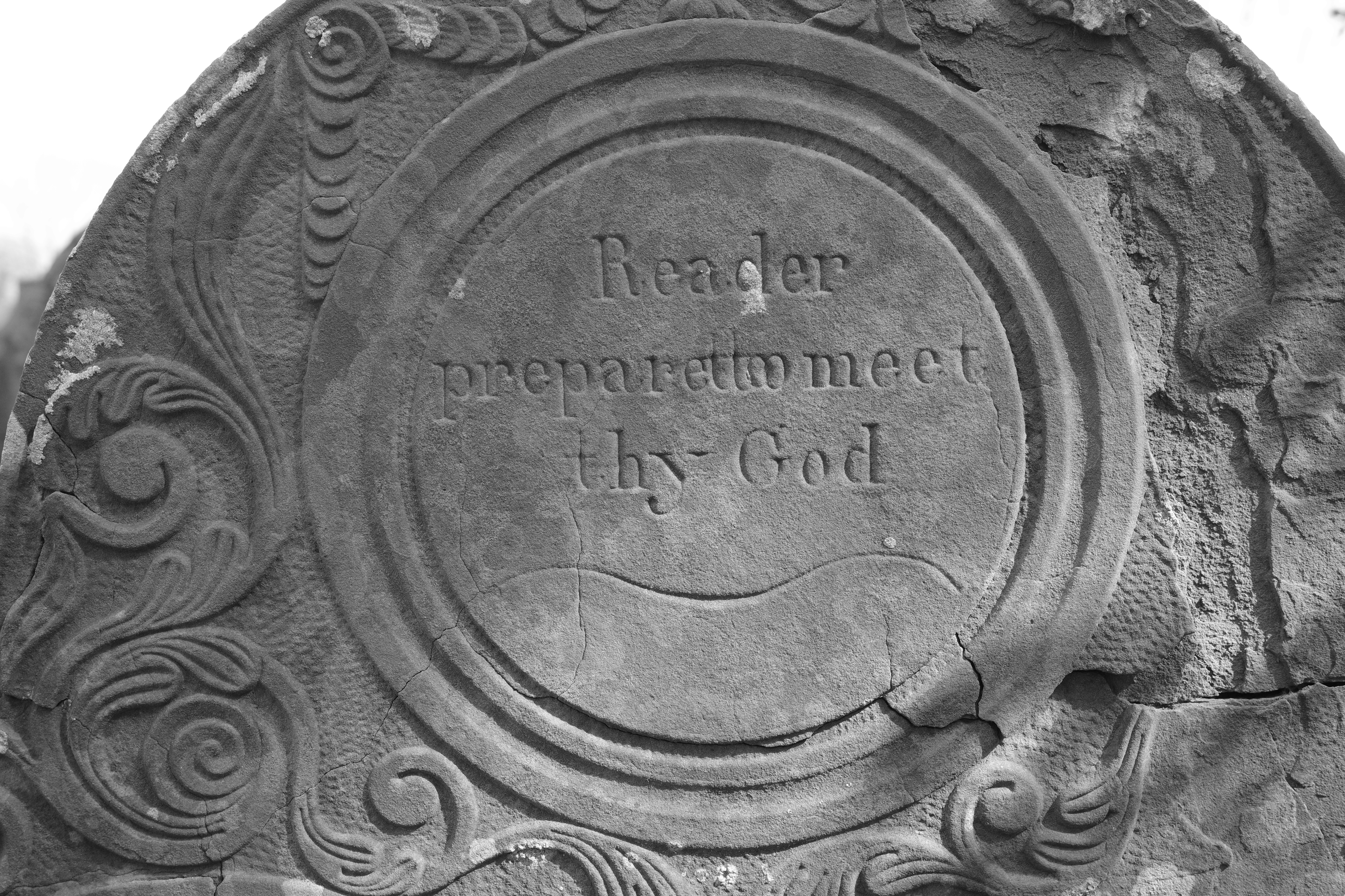 Carved circular inscription on weathered stone with decorative flourishes