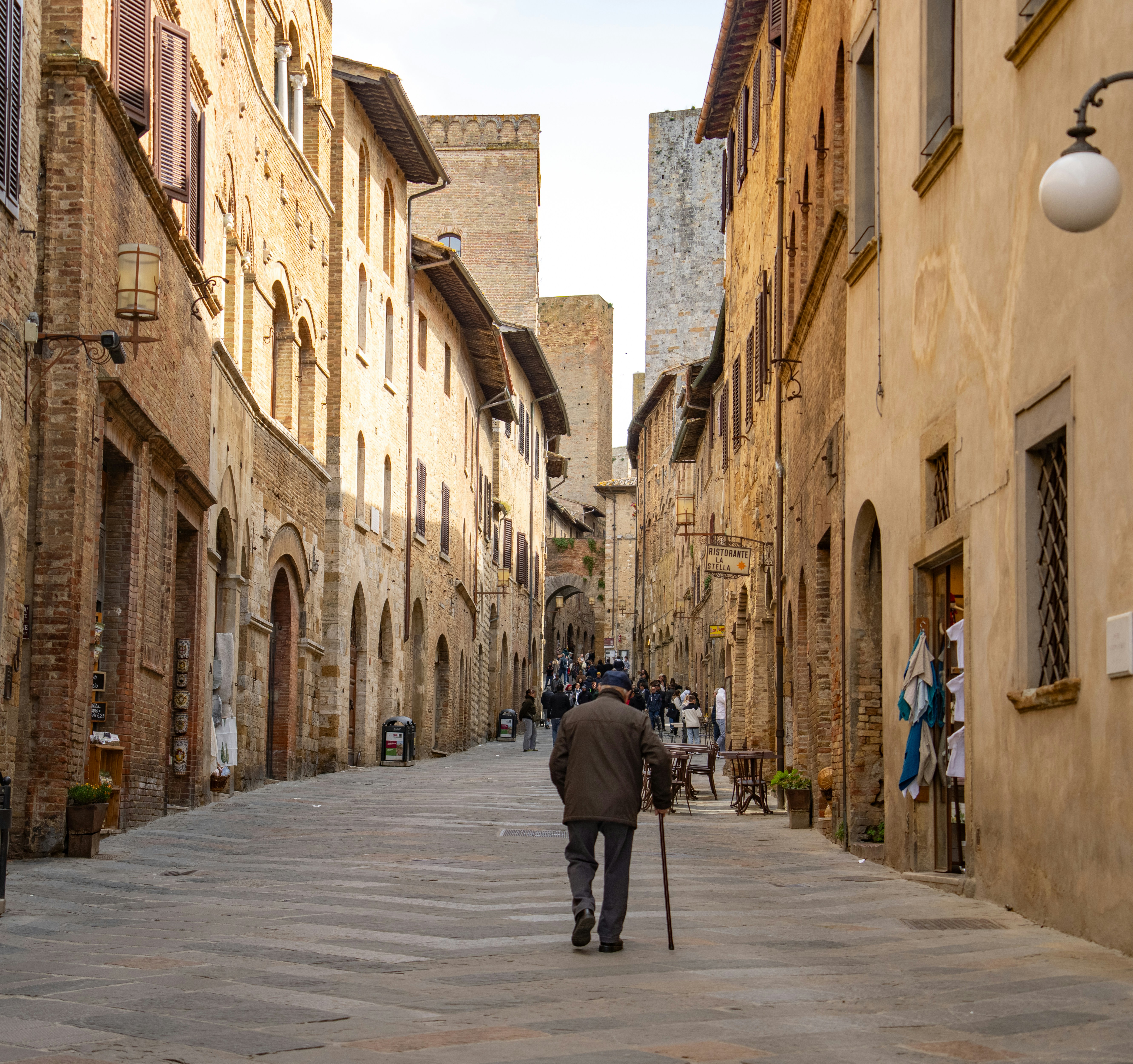 Wanderer with a Cane in a Sunlit Medieval Street