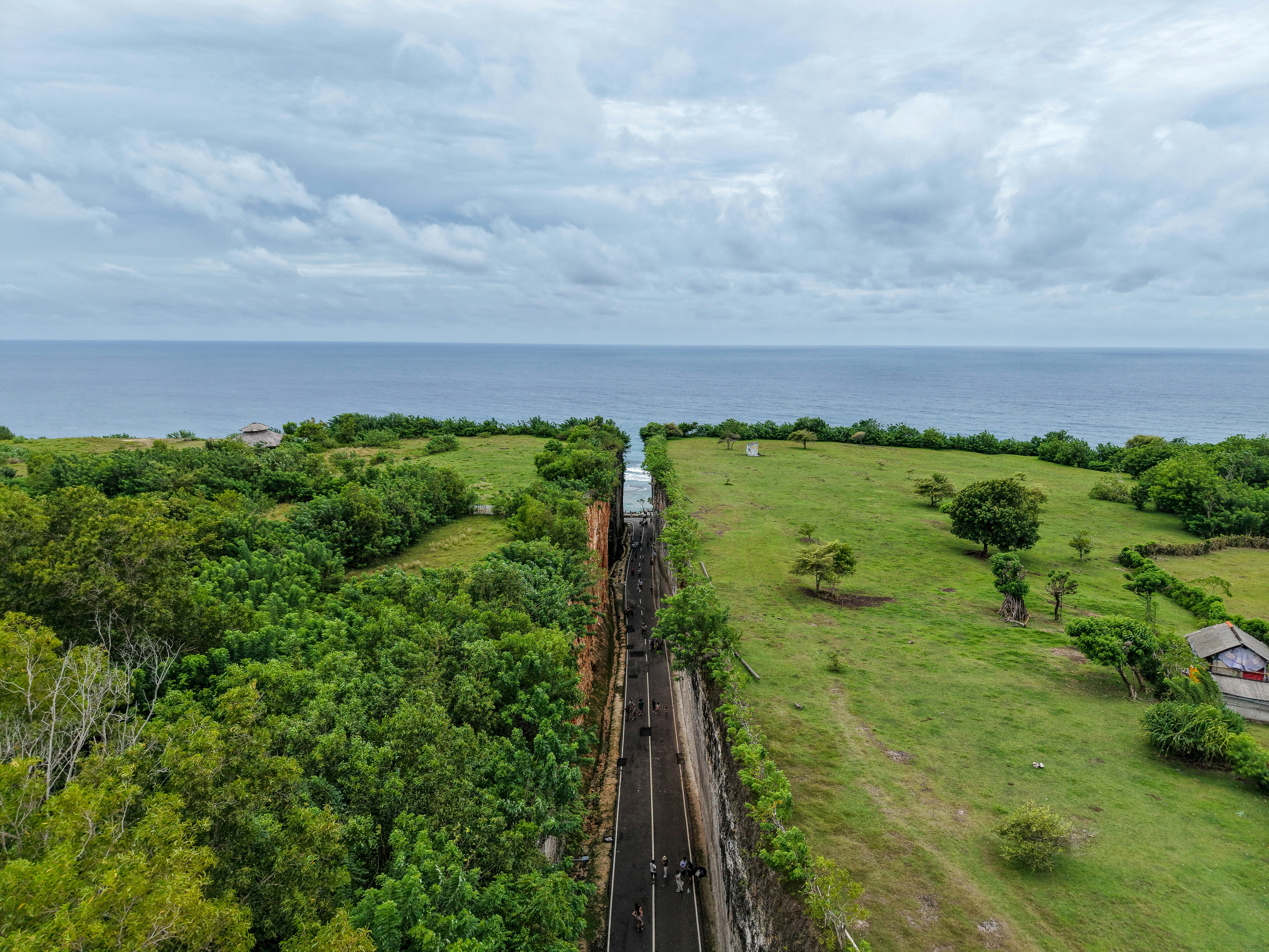 Coastal Gate: Aerial View of a Narrow Bruged Causeway Splitting Verdant Fields to Sea