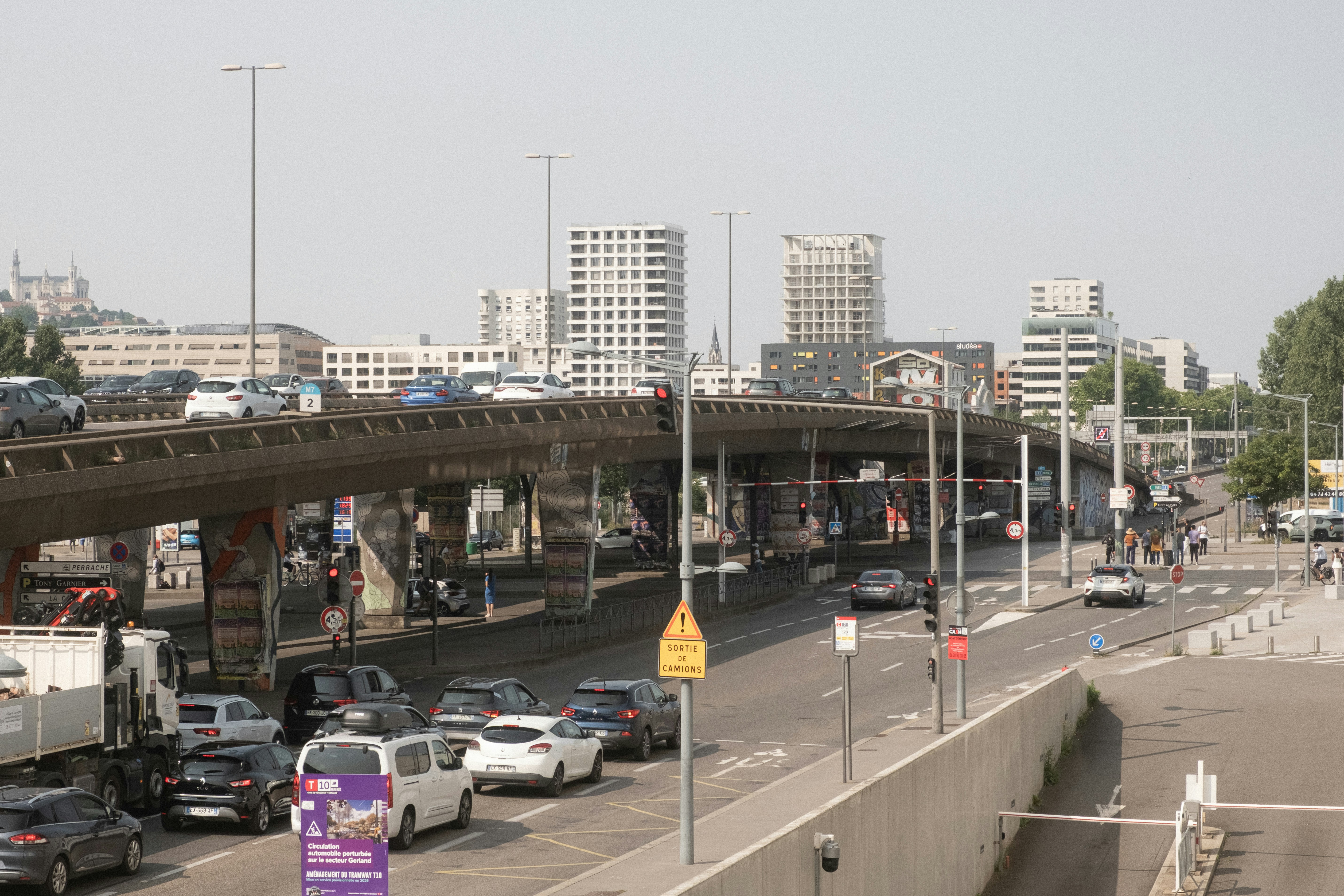 Busy highway overpass with heavy traffic and city skyline.