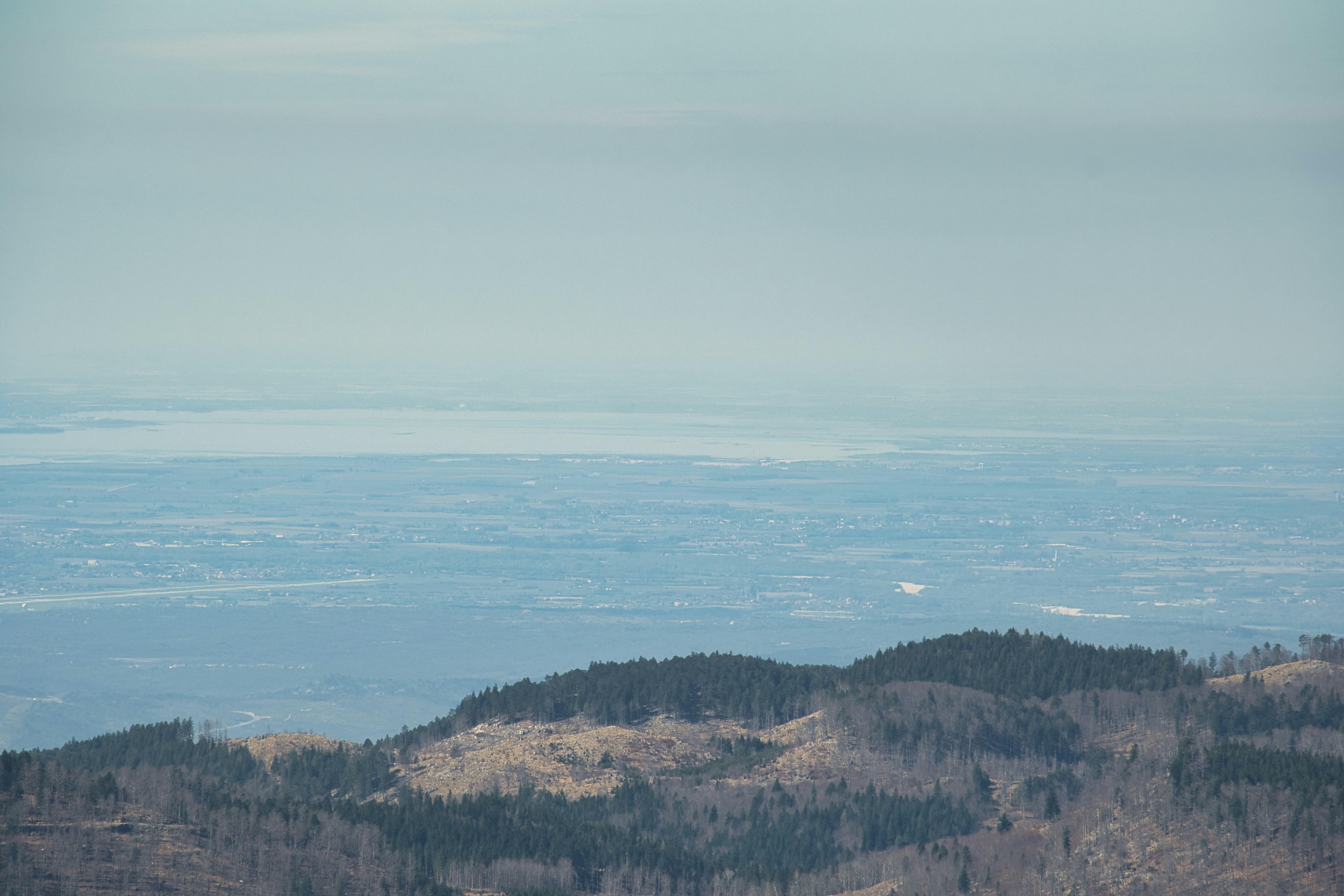 Mist over tranquil ridge: distant plains meet rolling forests