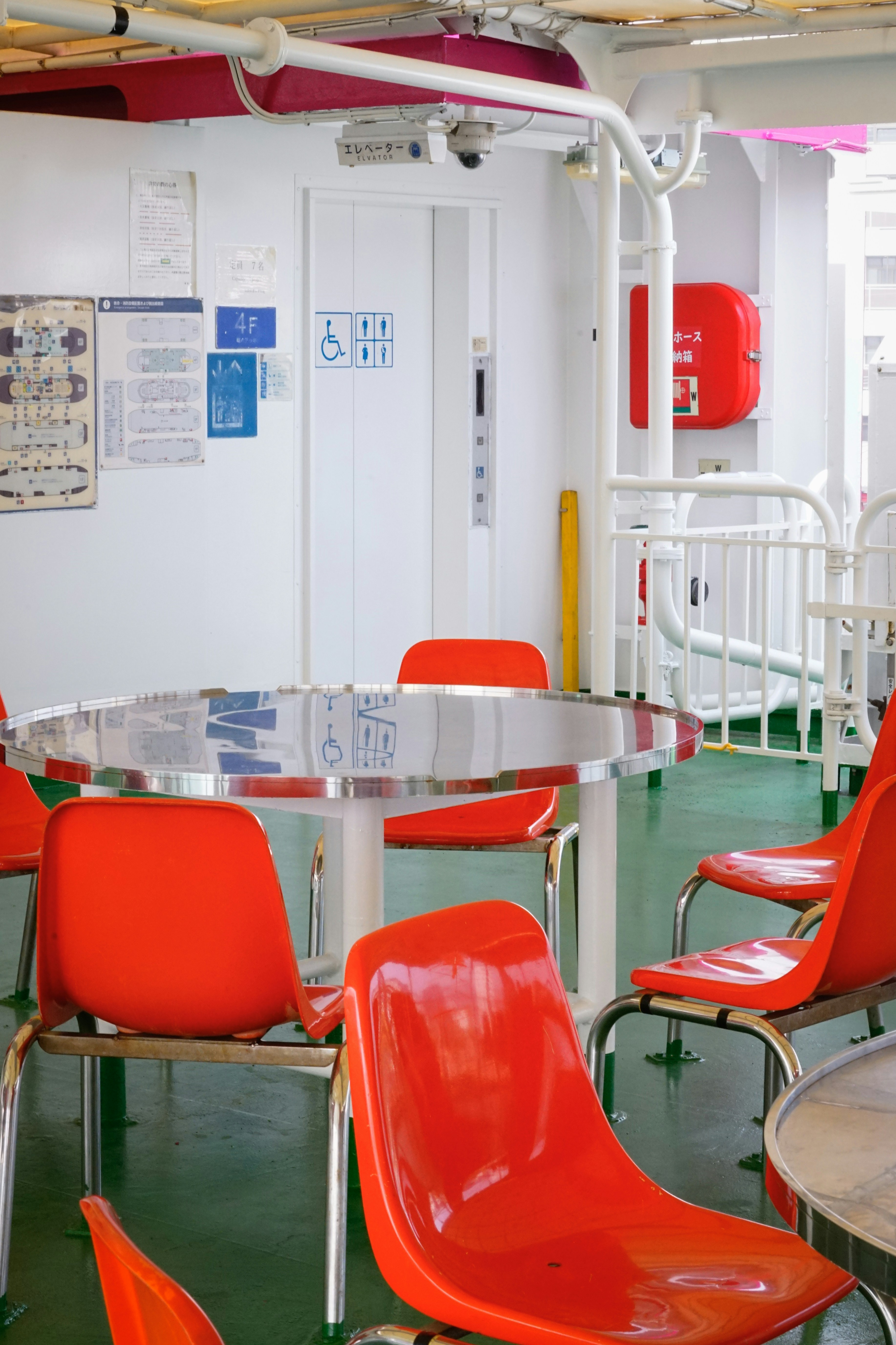 Red Chairs, Stainless Table, and Transit Corridor on a Ferry Deck