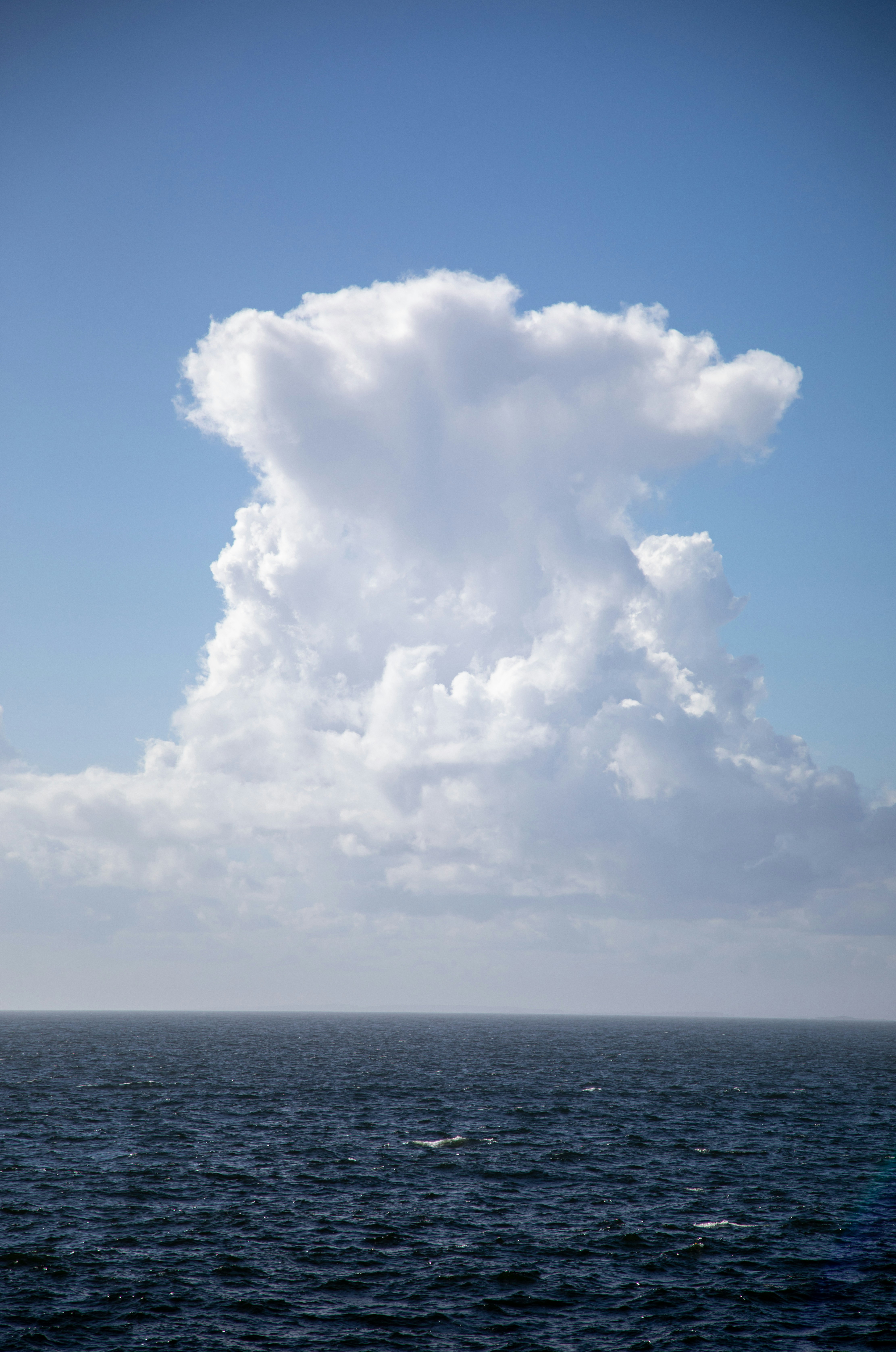 Cloud column over a calm sea: a solitary vertical spectacle at horizon