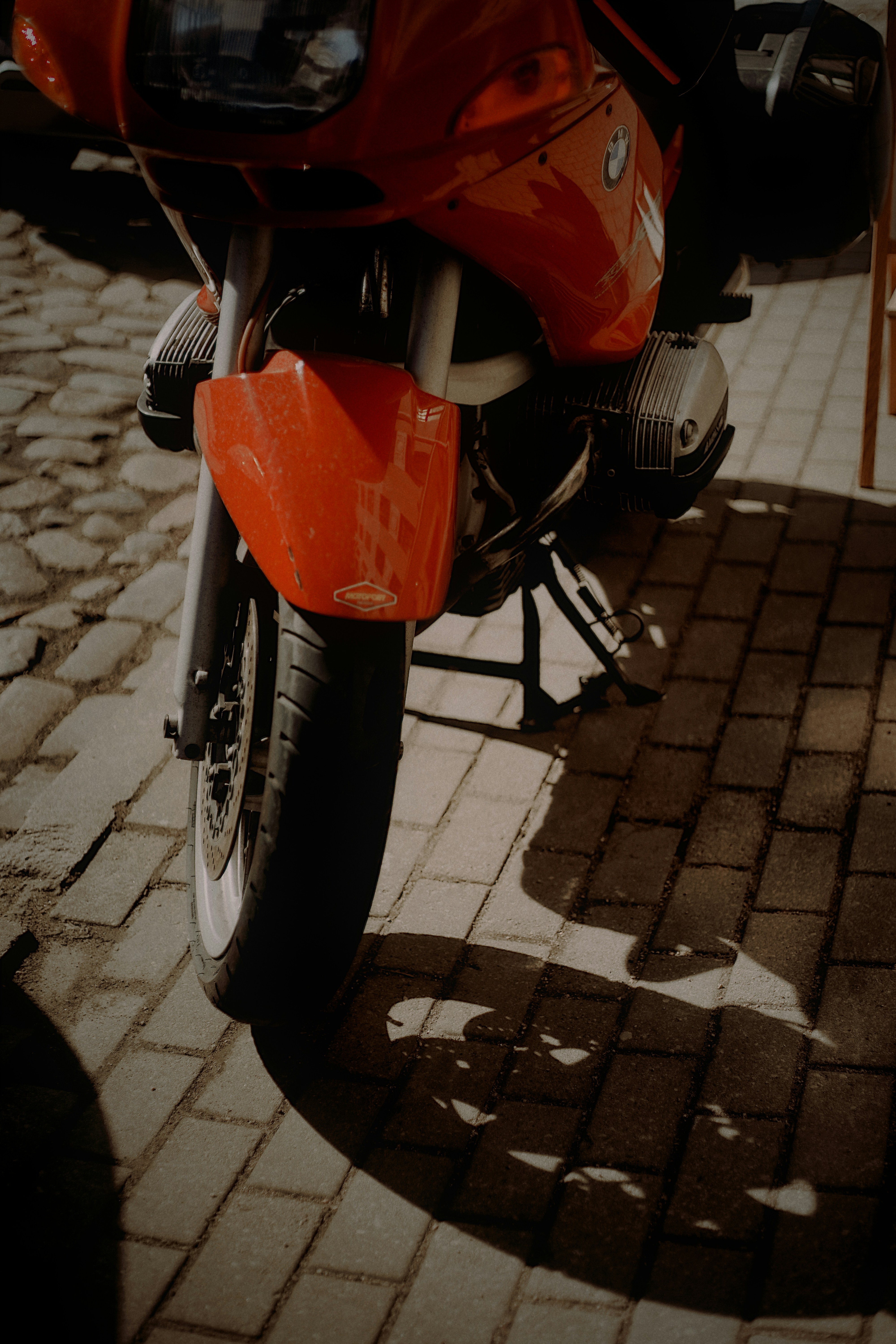 Orange Moto Front: A Shadowed Street Portrait