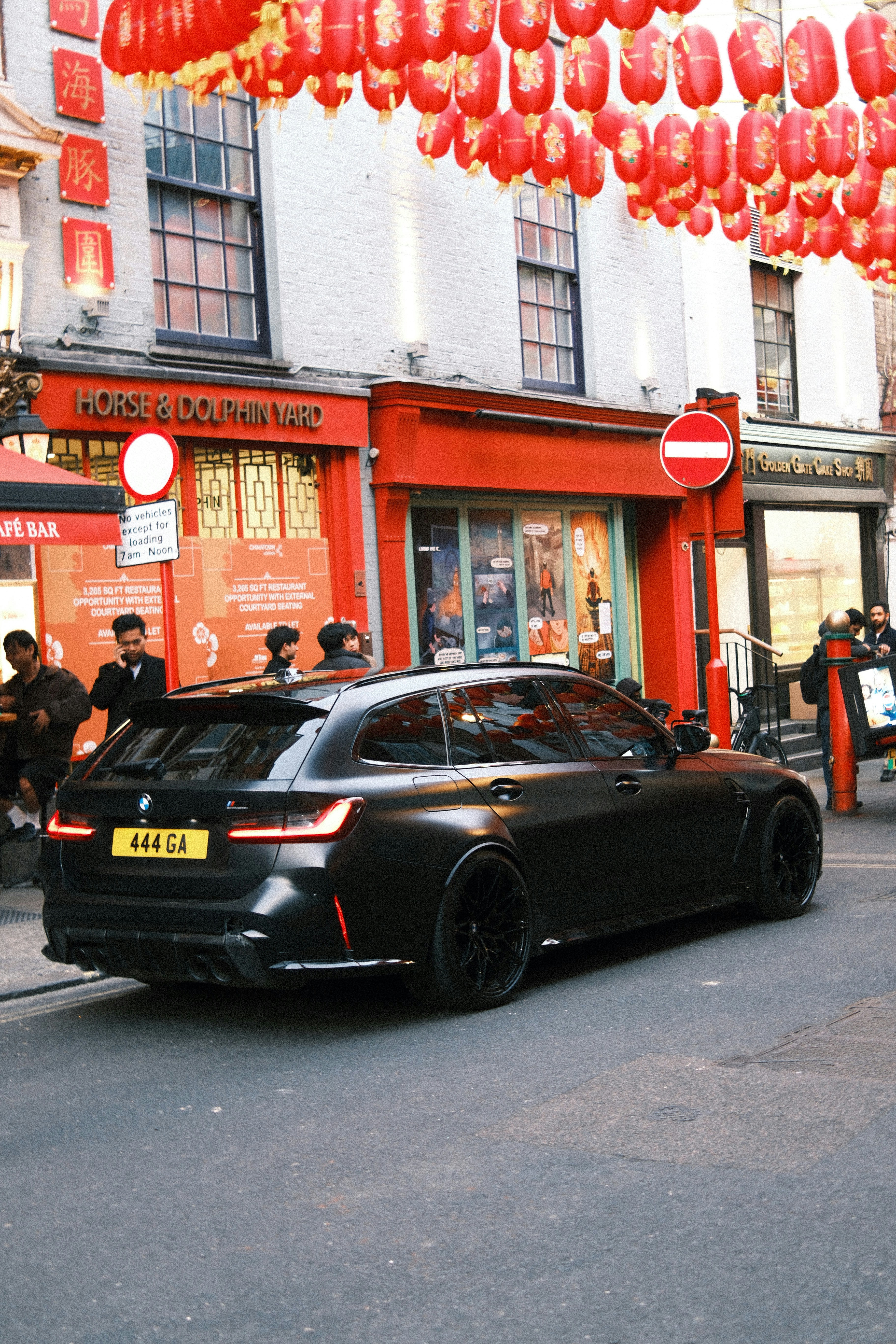 Black BMW Rests Under Red Lanterns on a Lively London Street