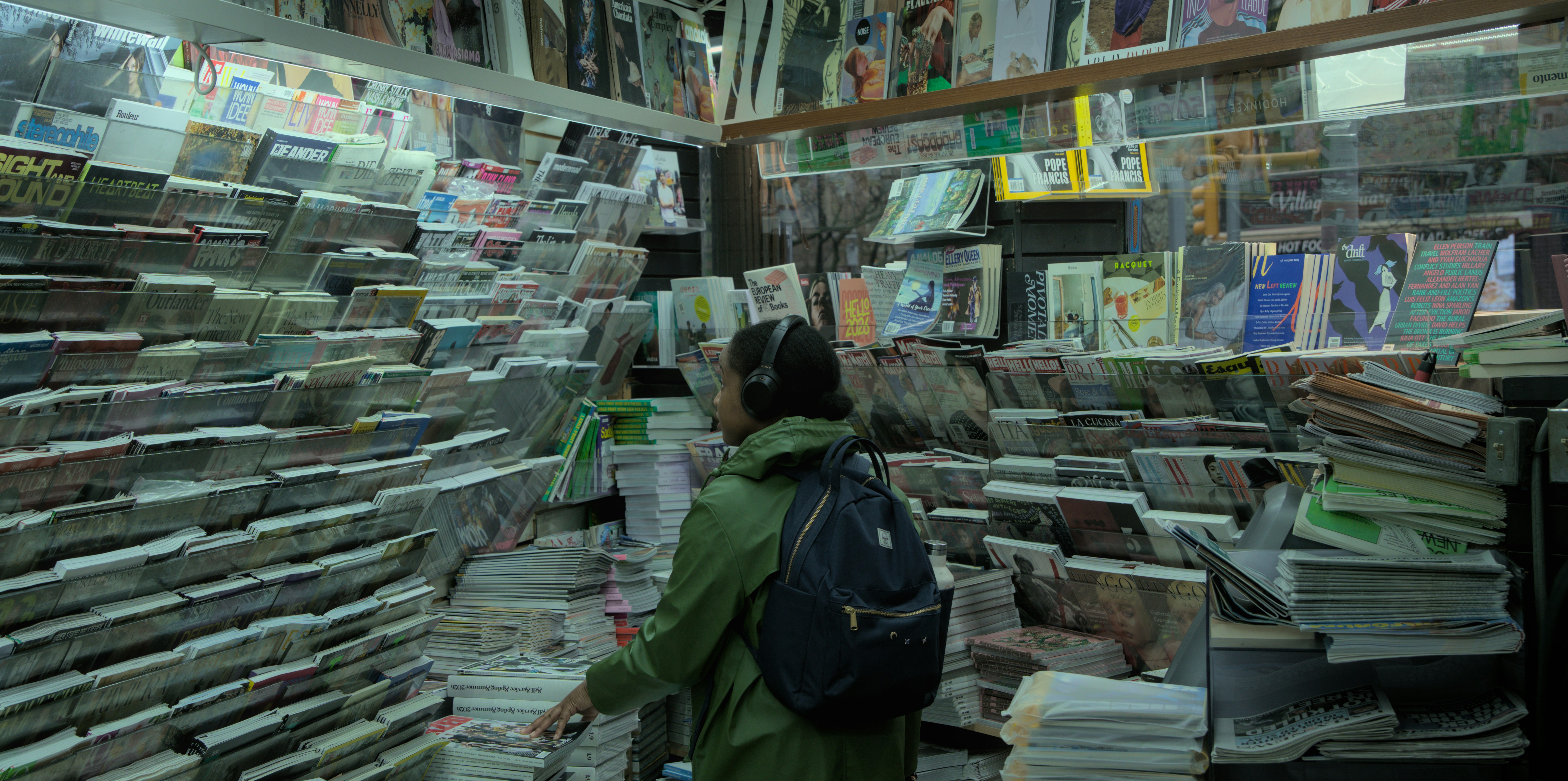 Into the Stacks: A Traveler Surrounded by Newsprint and Magazines
