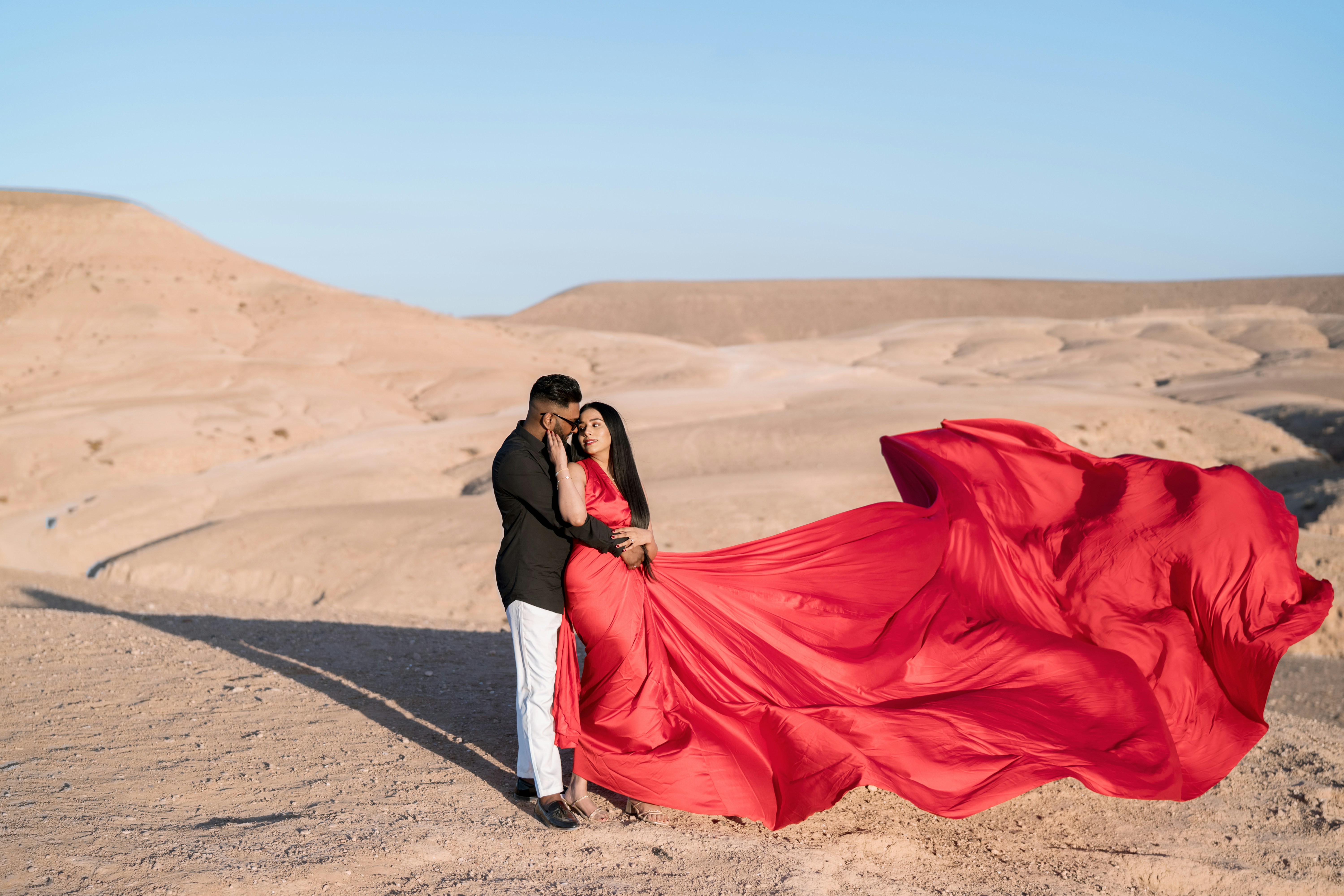 Couple in red dress embracing in desert landscape
