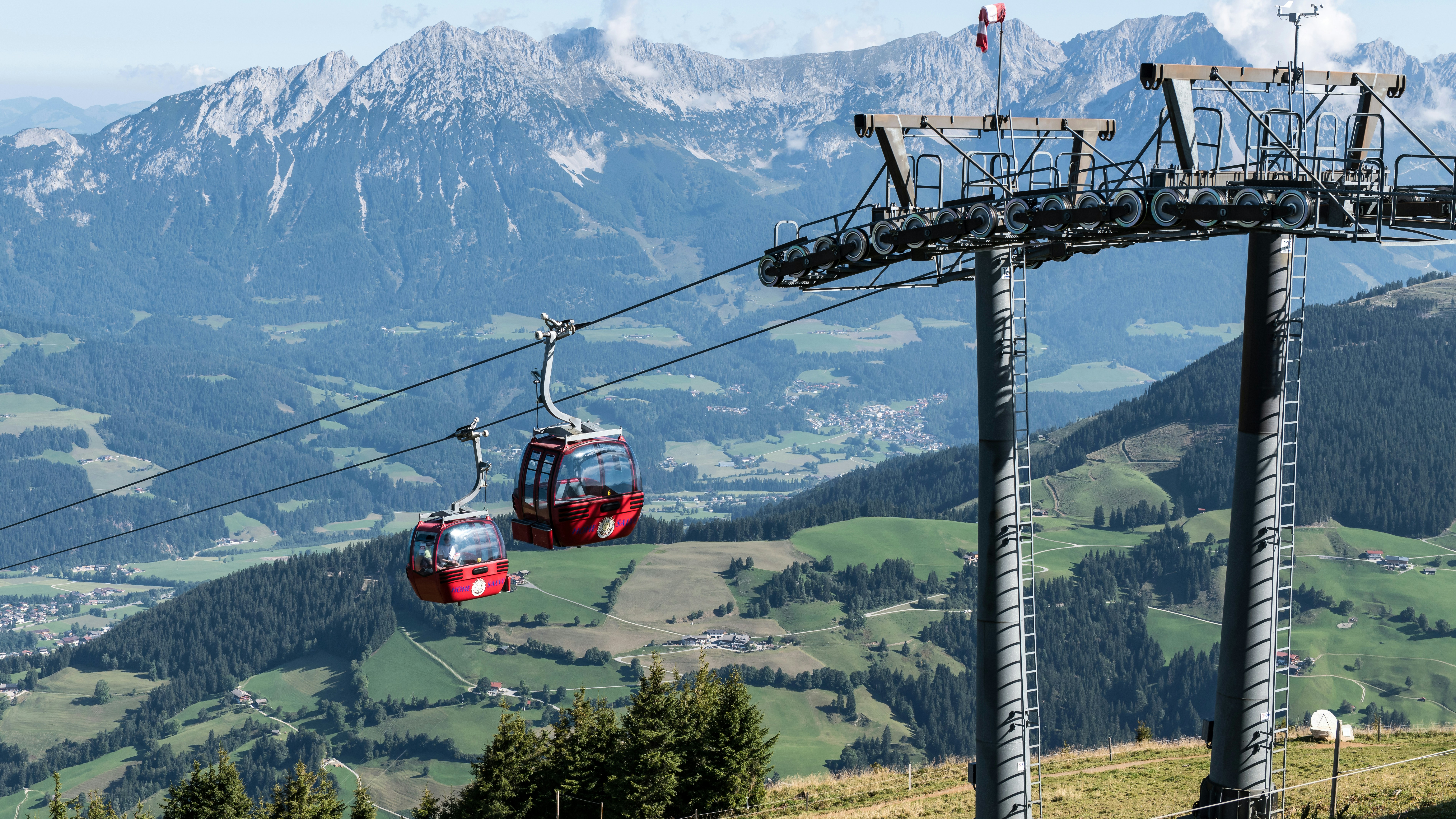 Cableway Across Alpine Valleys: Red Gondolas Amid Rugged Peaks