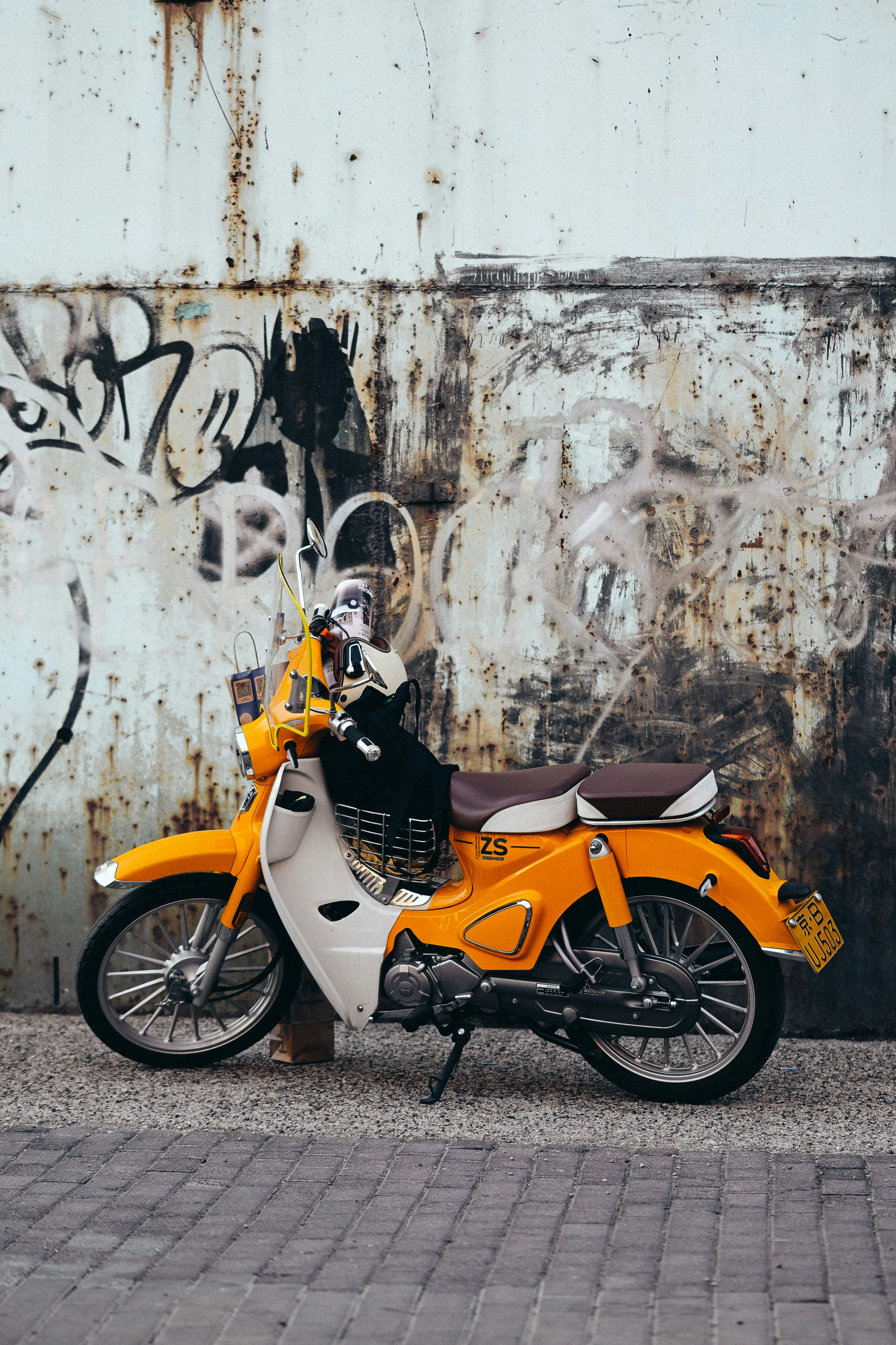 Orange airstream on rails: a vintage motorcycle portrait against a graffiti wall
