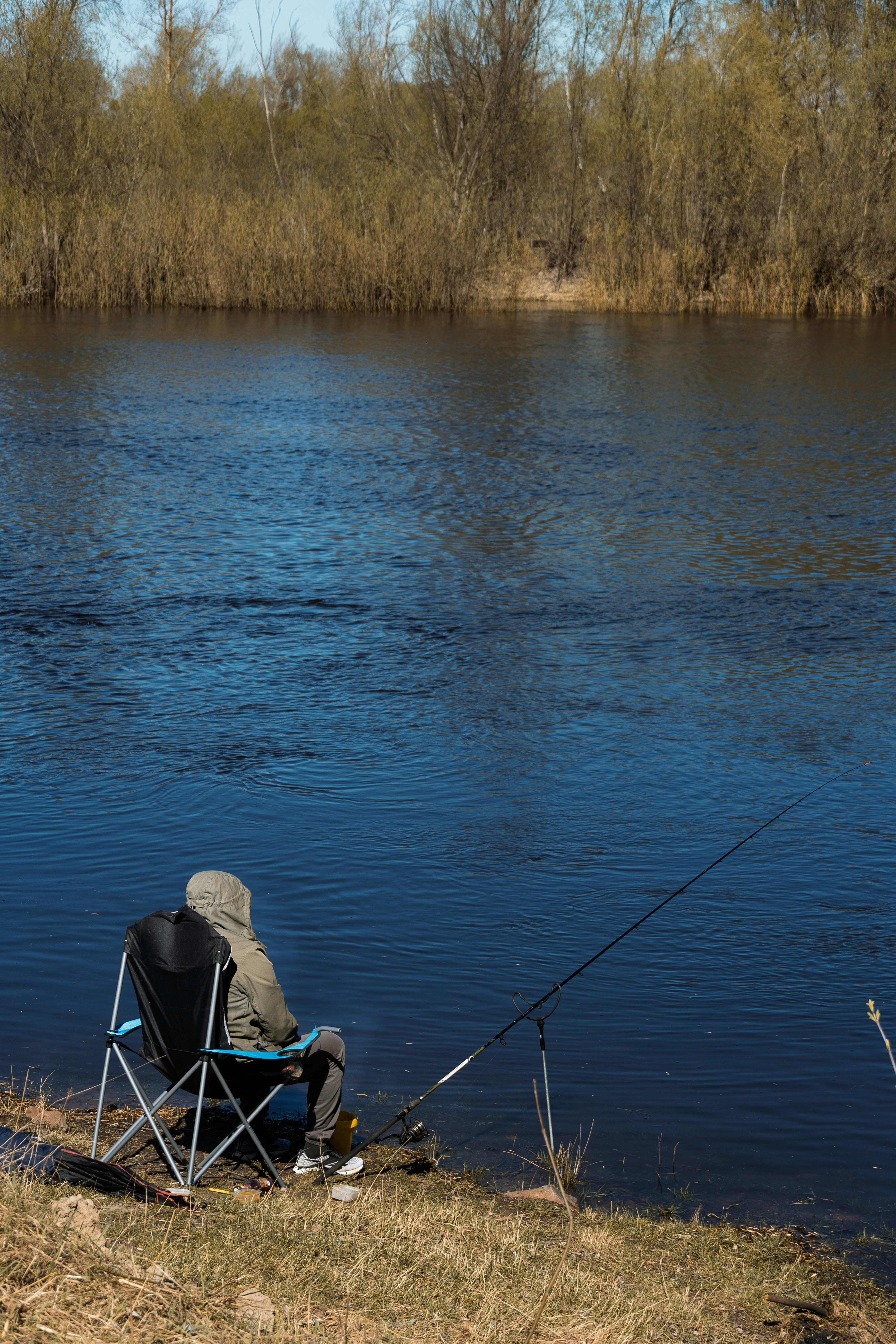 Relaxed Angler at the Riverside: Quiet Focus by the Water