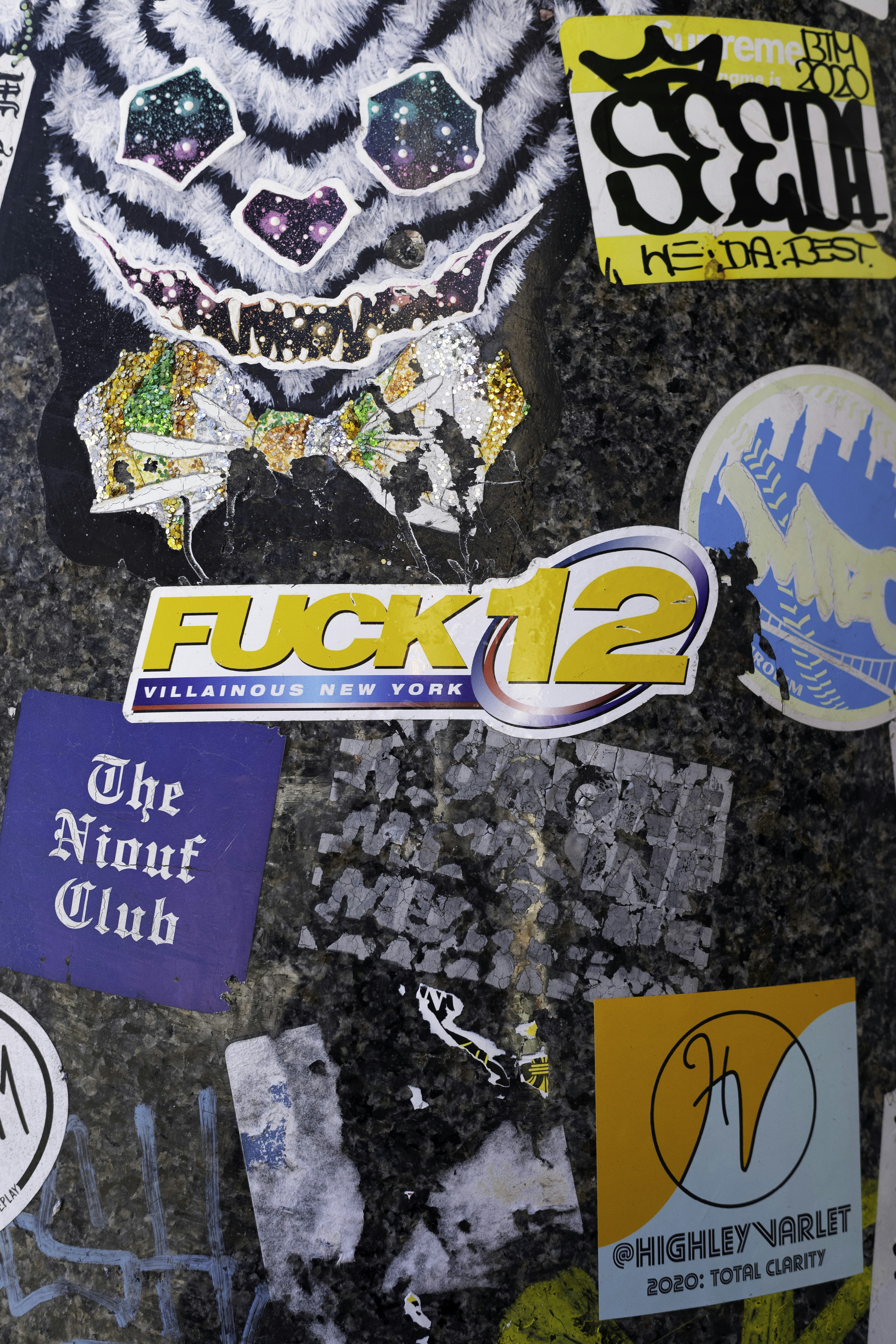 Sticker mosaic on a gritty urban wall: chaos of col silks and neon skulls