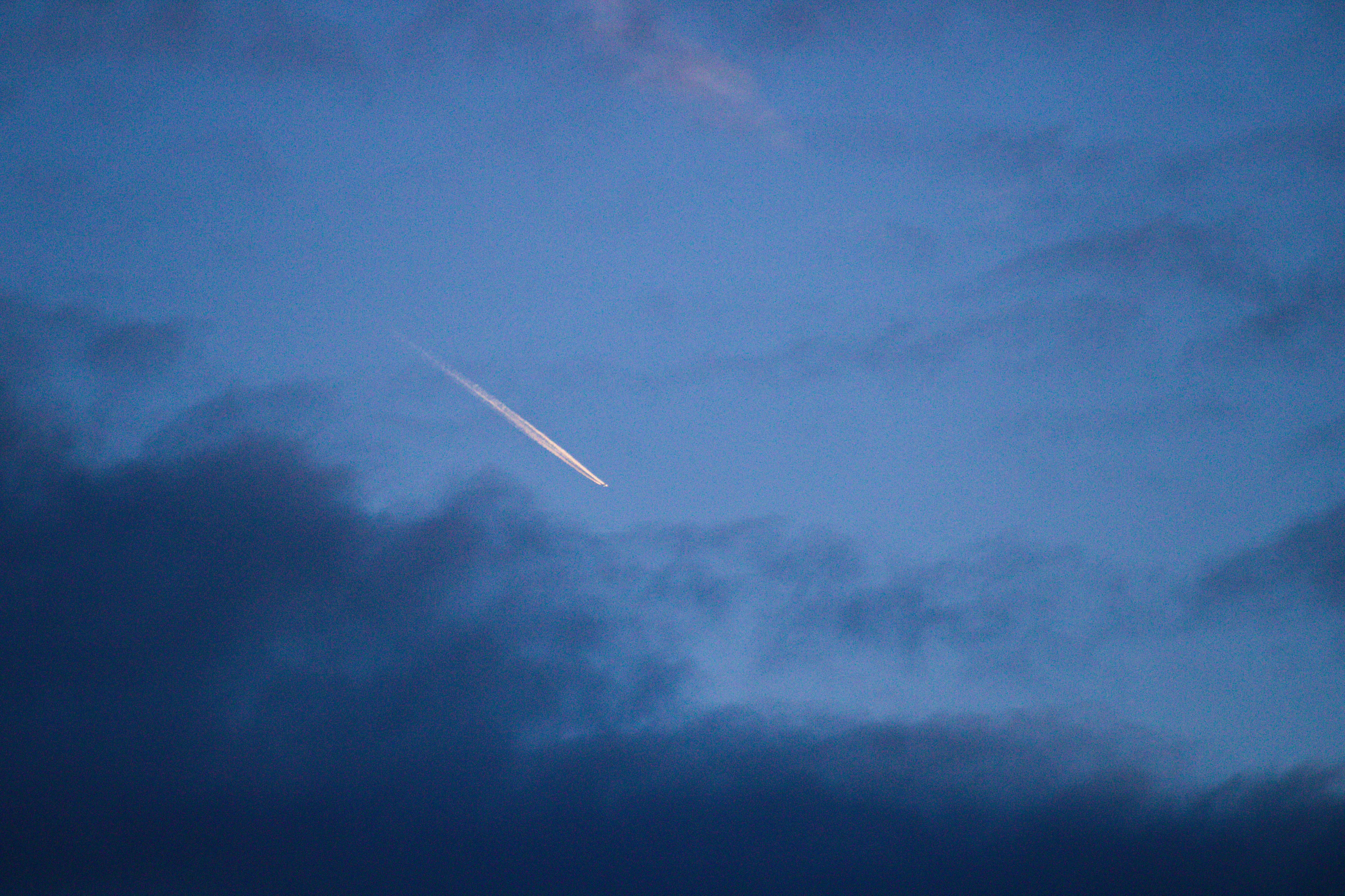 Blue Hour Jet Trail Slicing Through Cloud Veil
