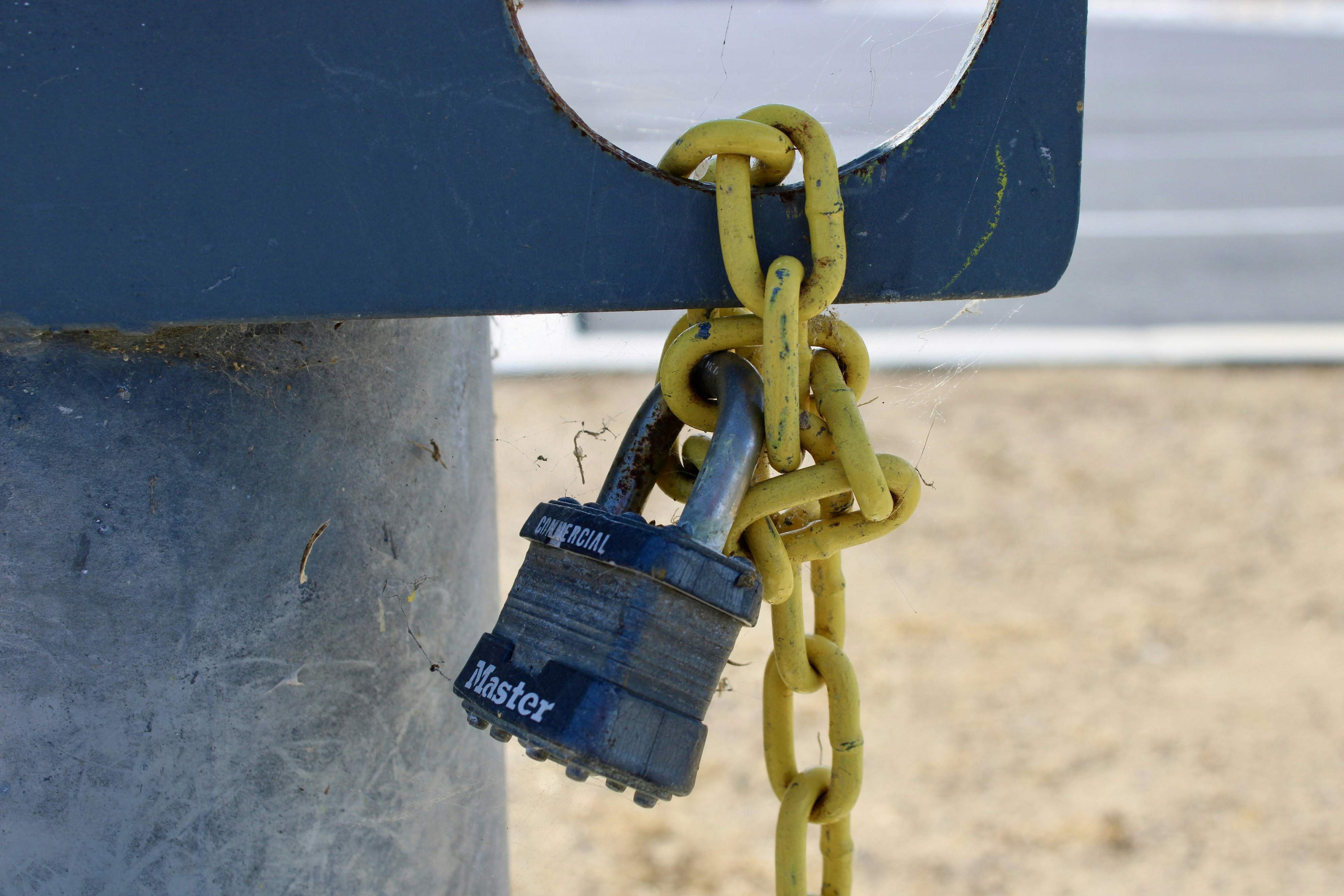Locked in Blue: A Weathered Padlock on a Yellow Chain