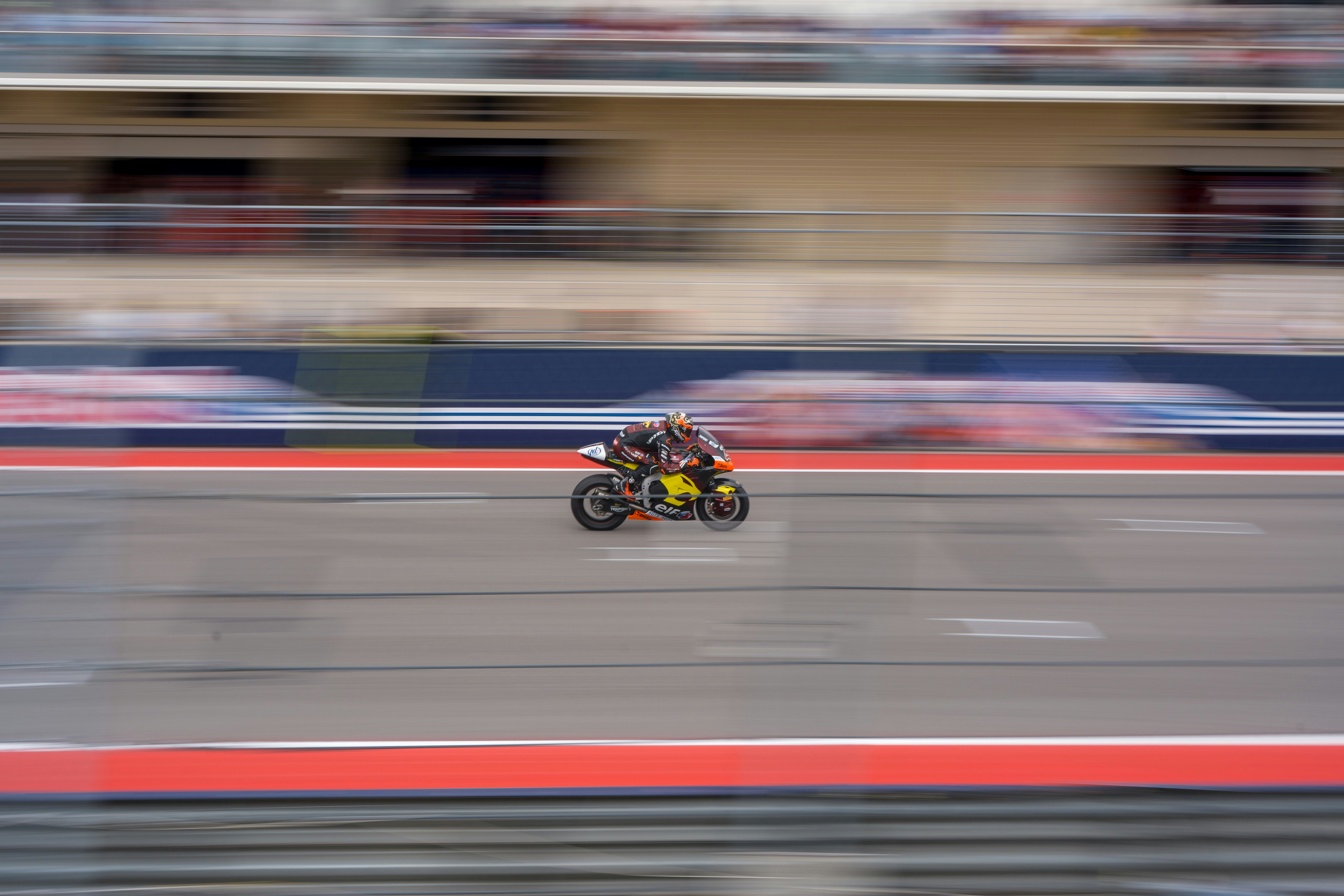 Blurred Speedway: Focused Rider in a Stretching Motion