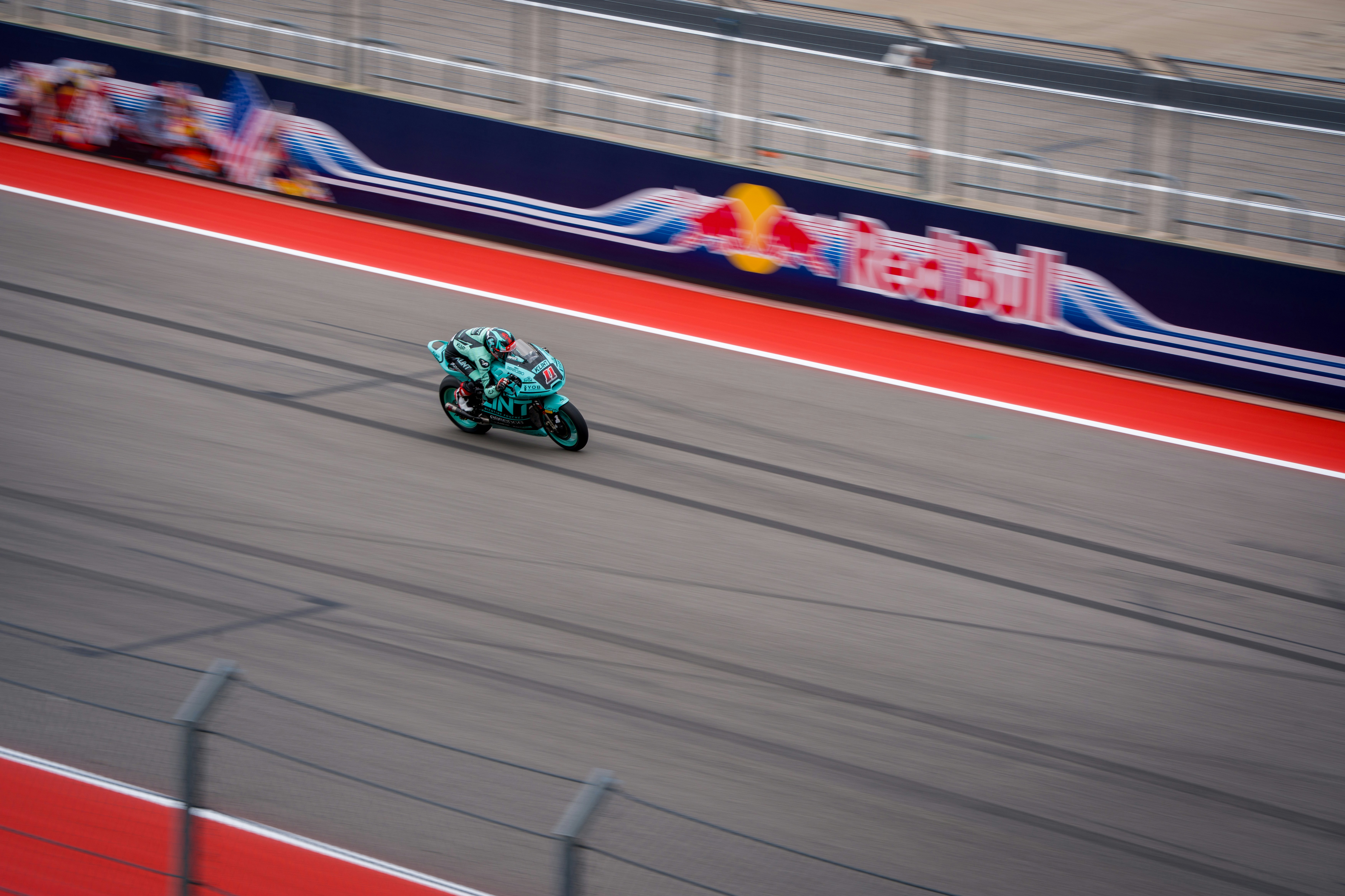 Green Moto Blurs into Red Track: A Lone Rider under Red Bull Ridge